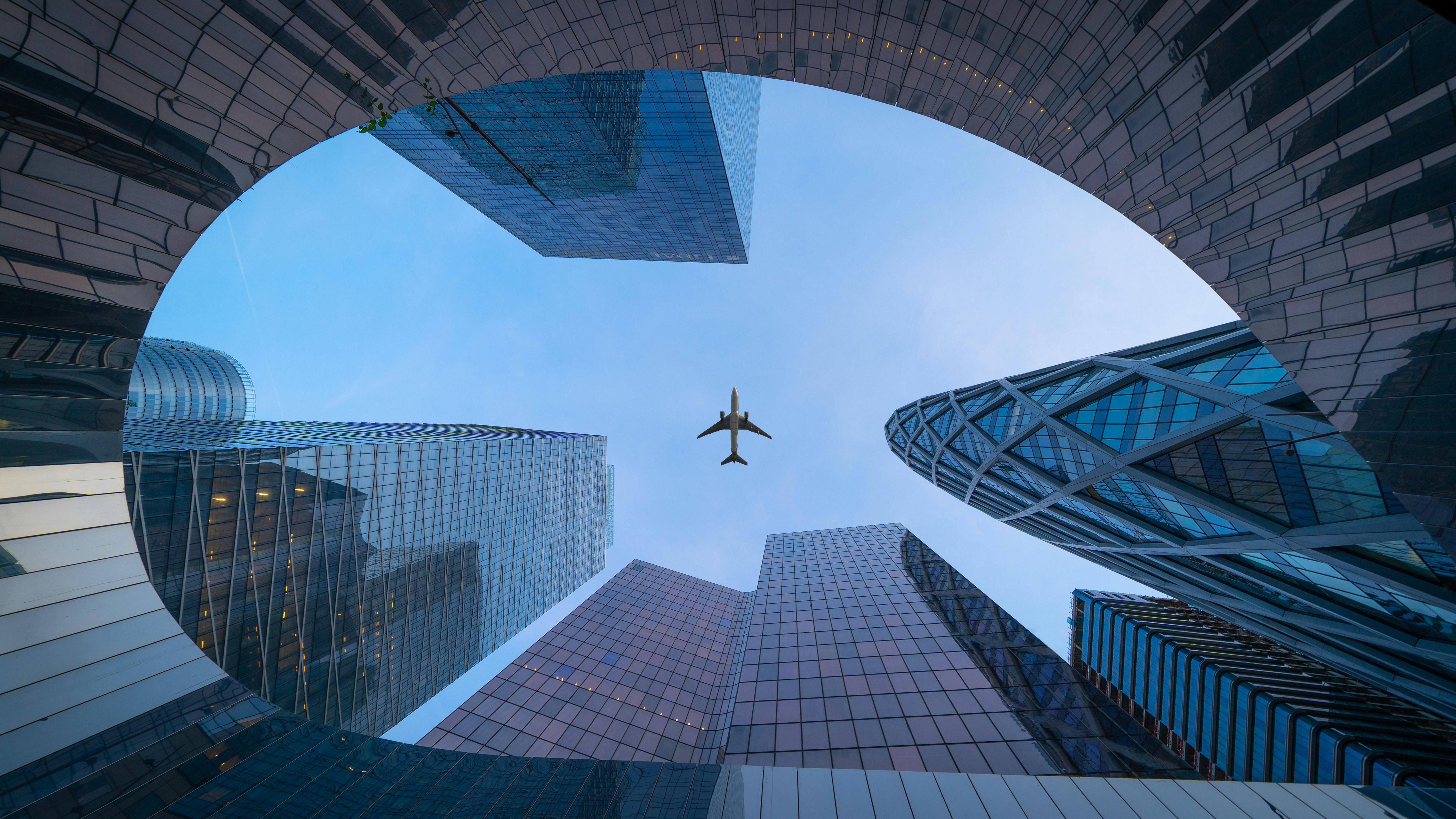 Airplane Flying over a Complex of Modern Skyscrapers · Free Stock Photo