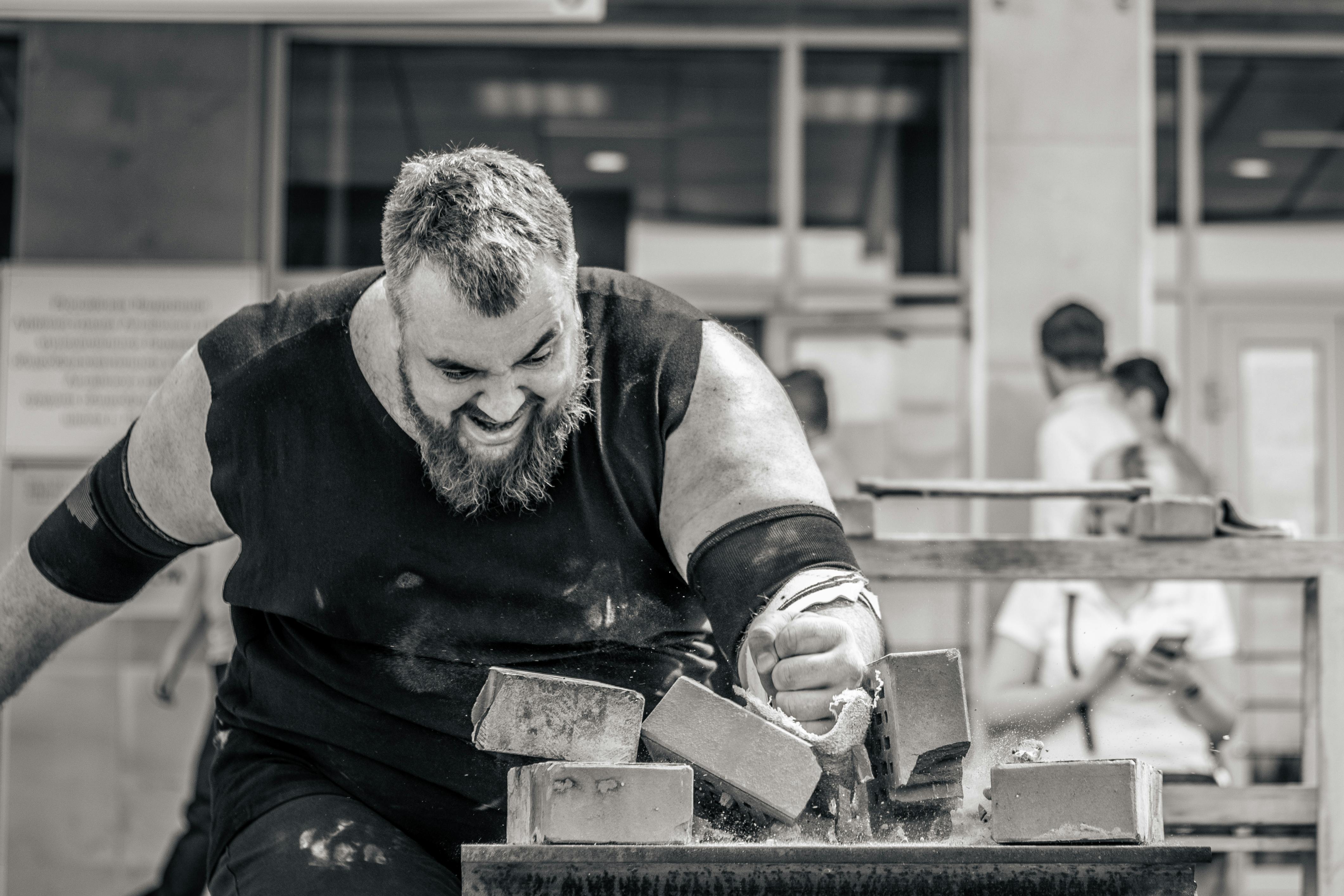 Grayscale Photo of a Man Smashing Bricks · Free Stock Photo