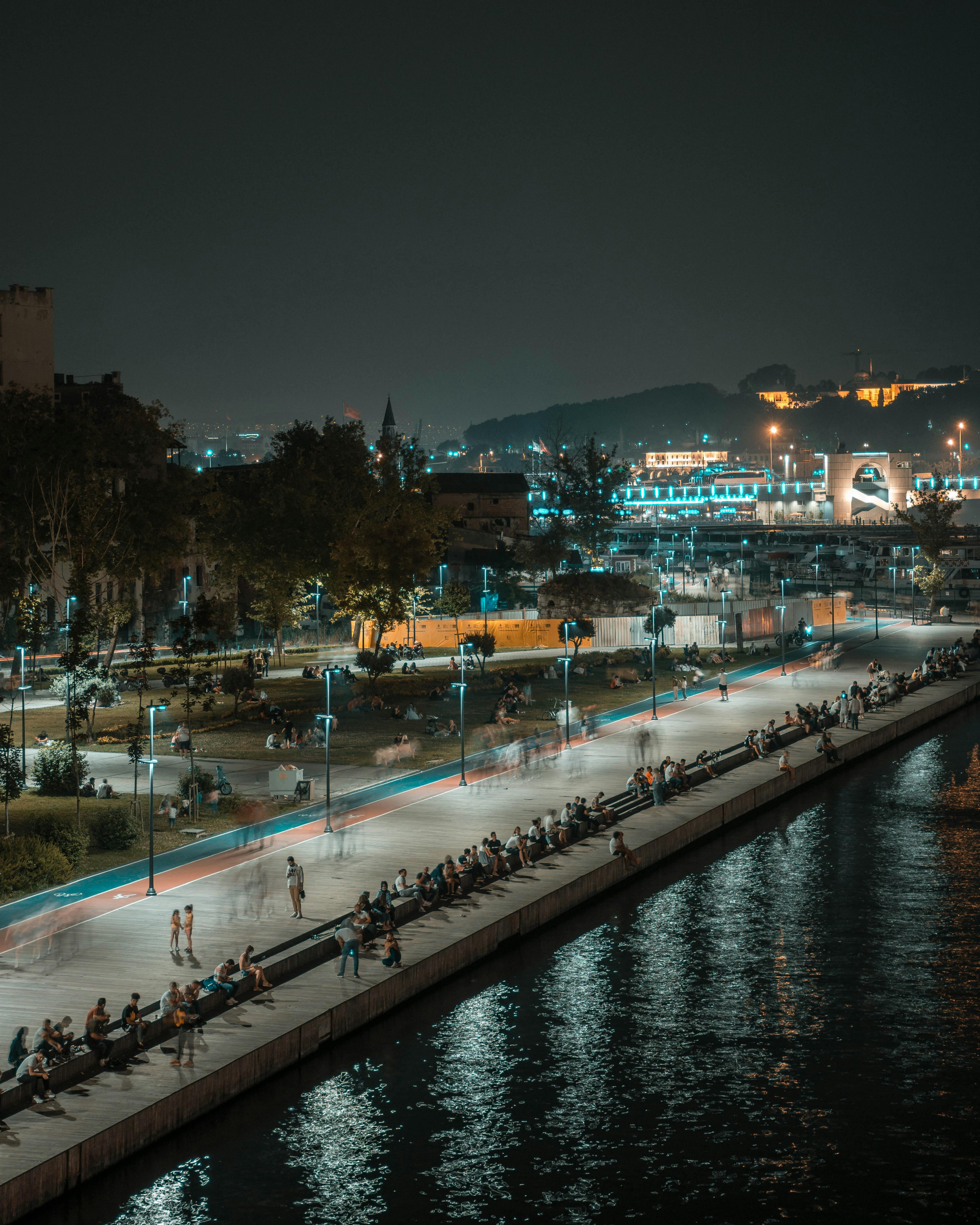 People Sitting at City River Bank at Night · Free Stock Photo