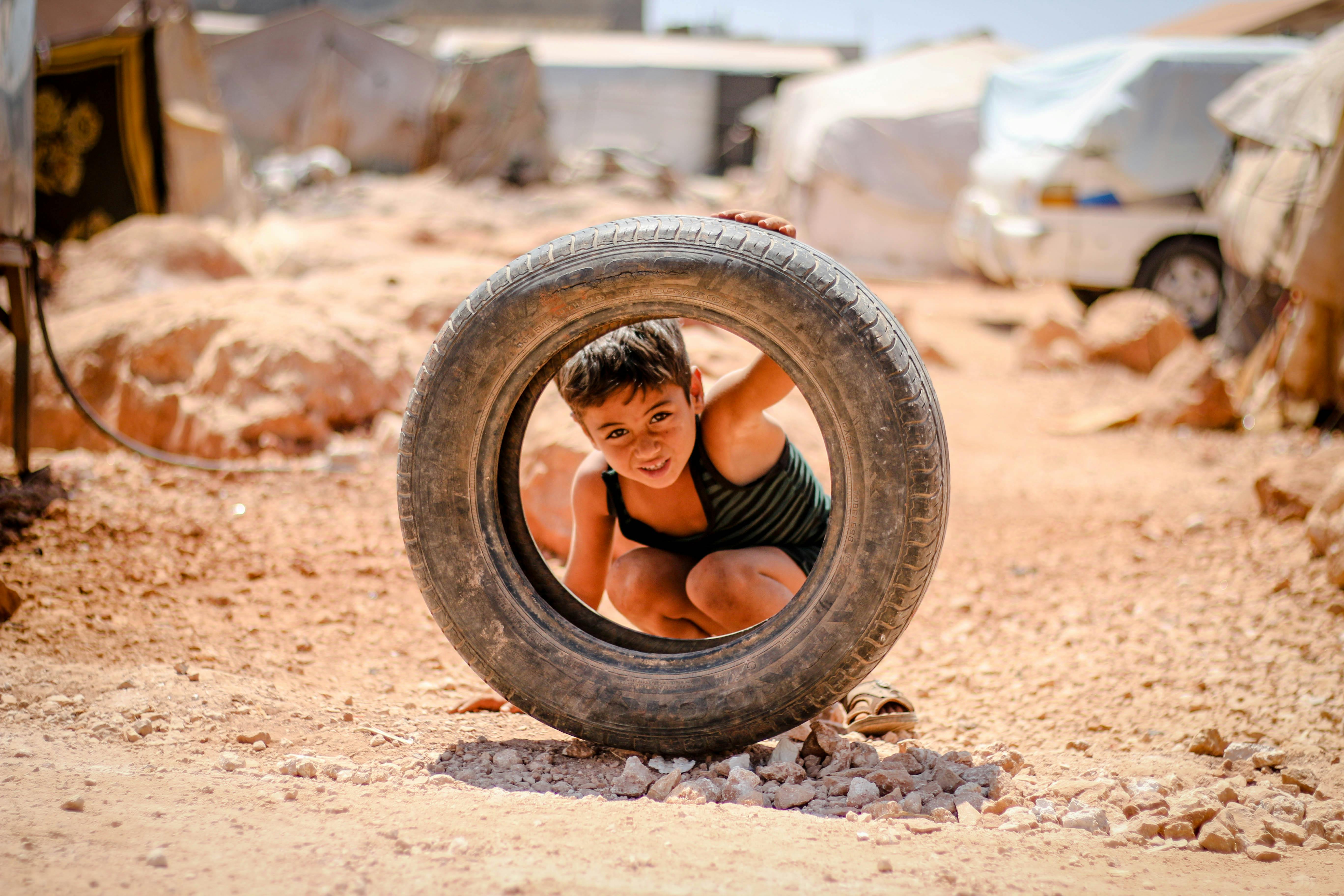A Boy Looking Through a Tire's Hole · Free Stock Photo
