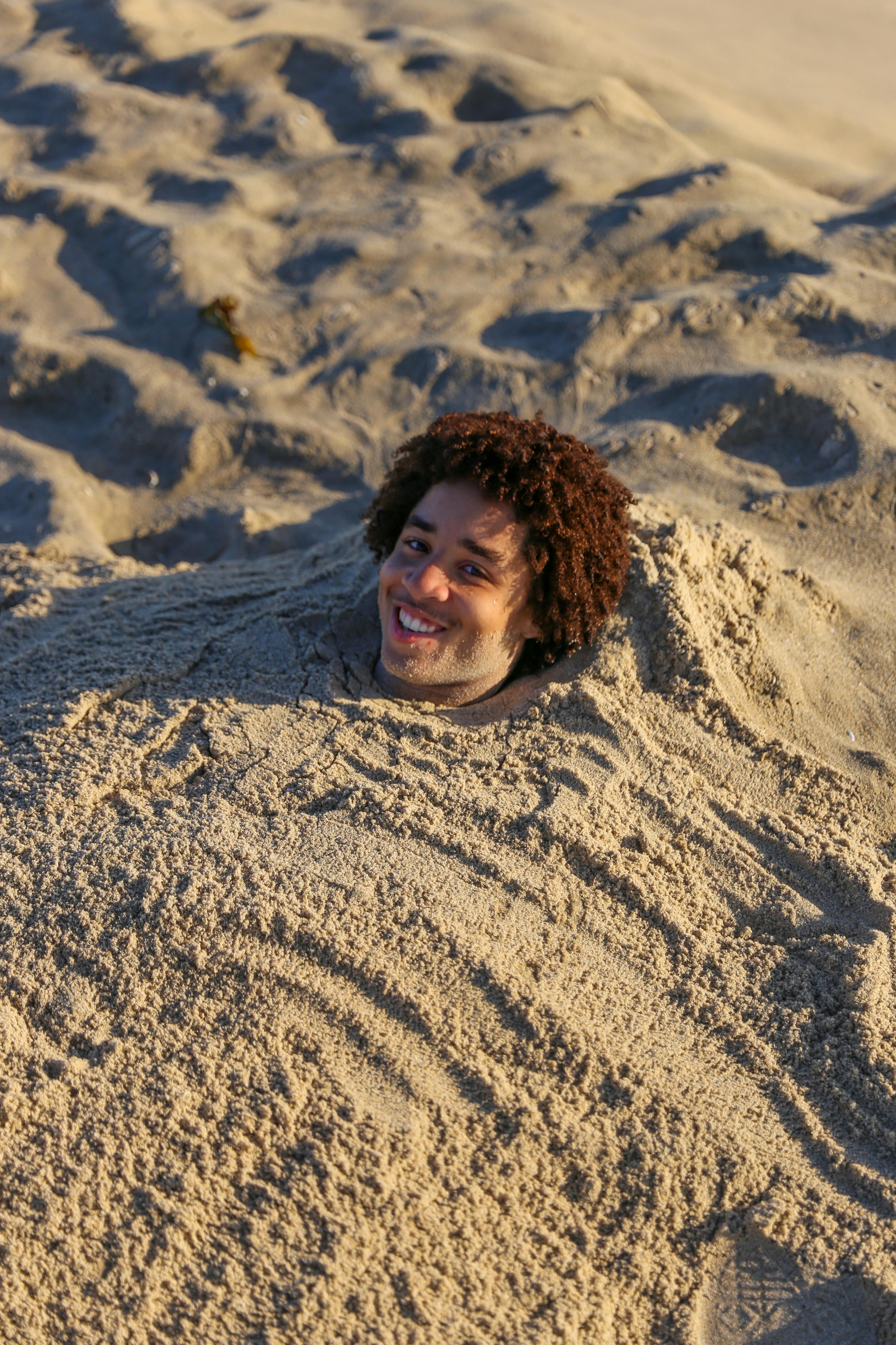 Smiling Man Covered with Brown Sand · Free Stock Photo