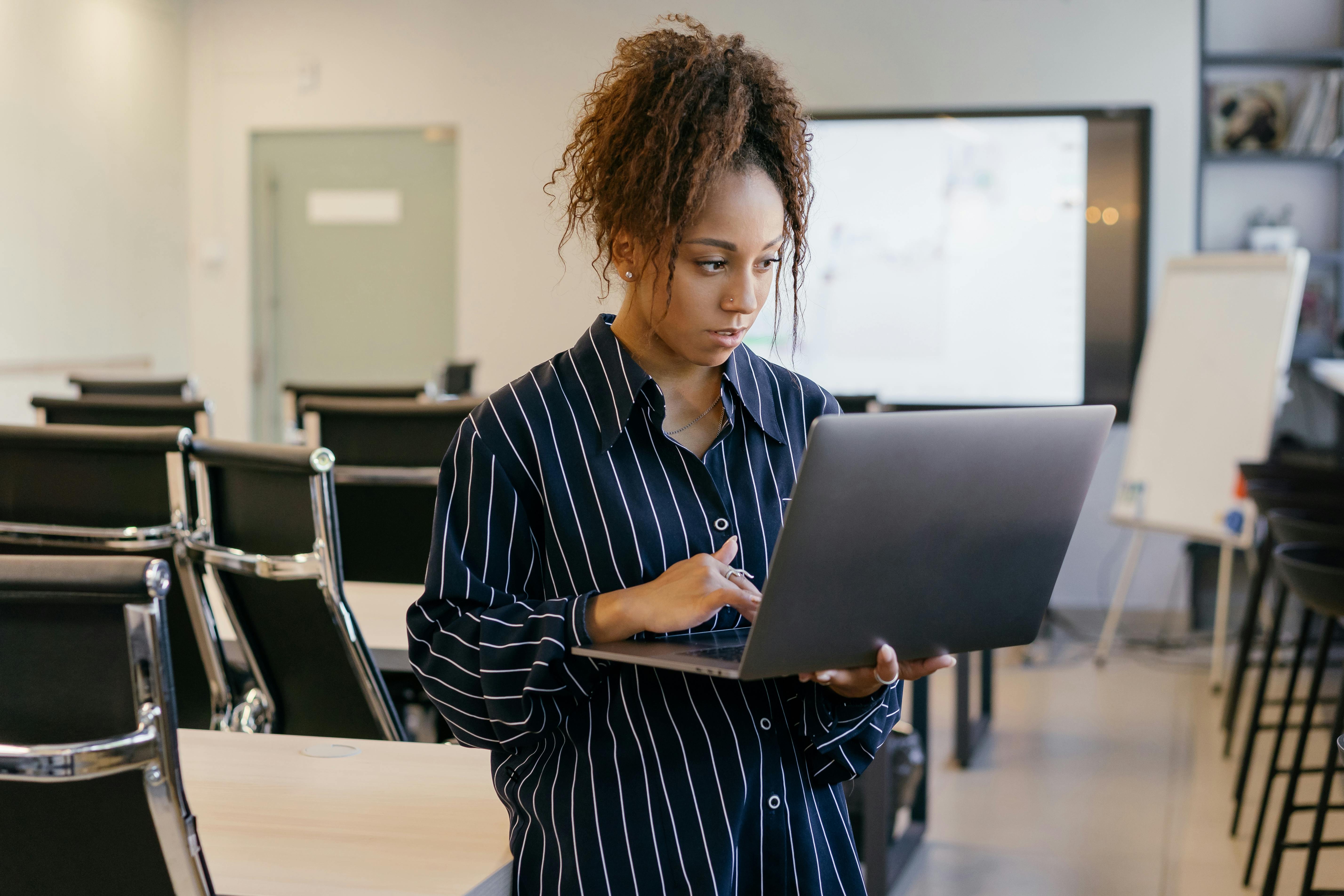 A Woman Standing While Using a Laptop · Free Stock Photo