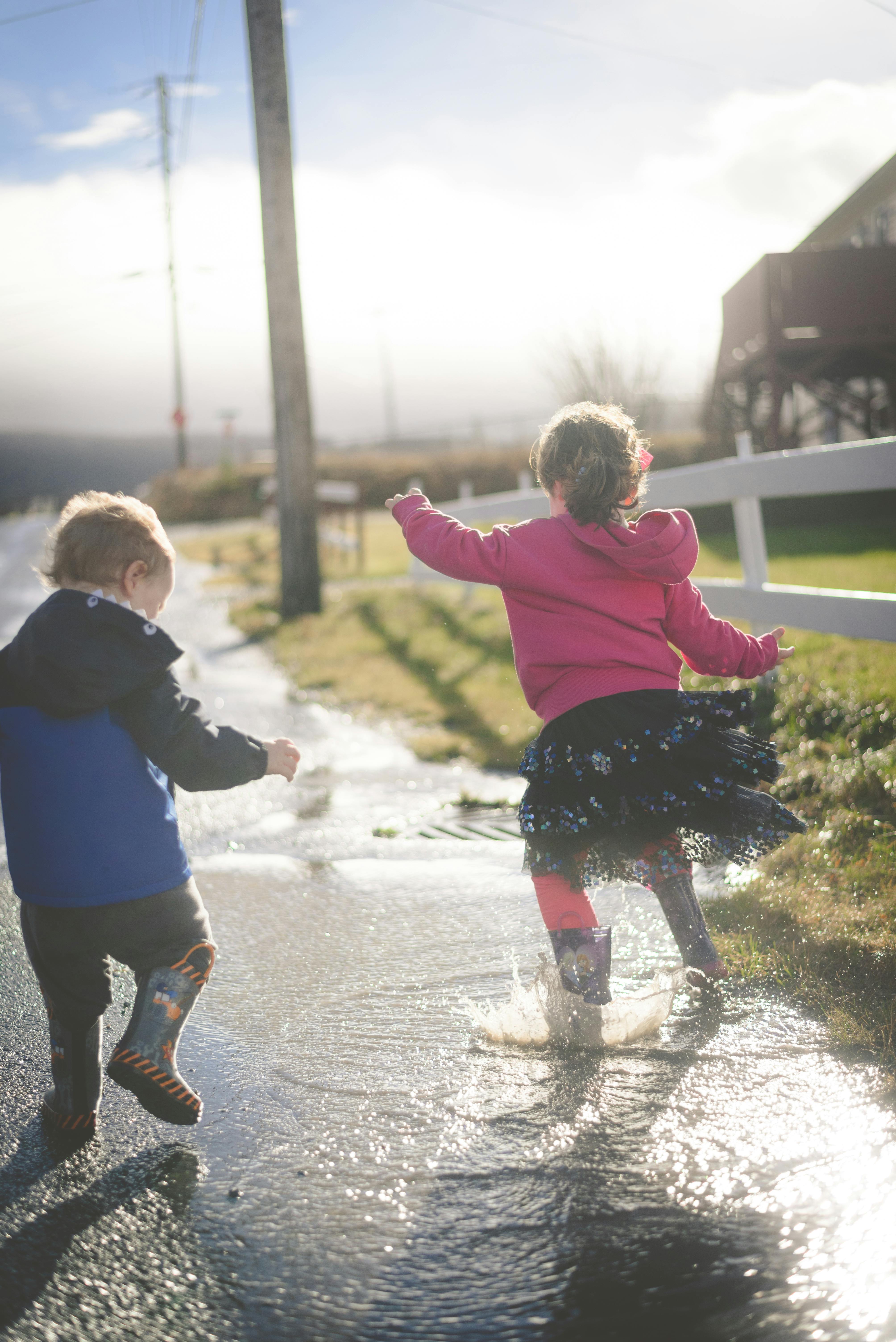 A Girl and Boy Running on the Wet Road · Free Stock Photo