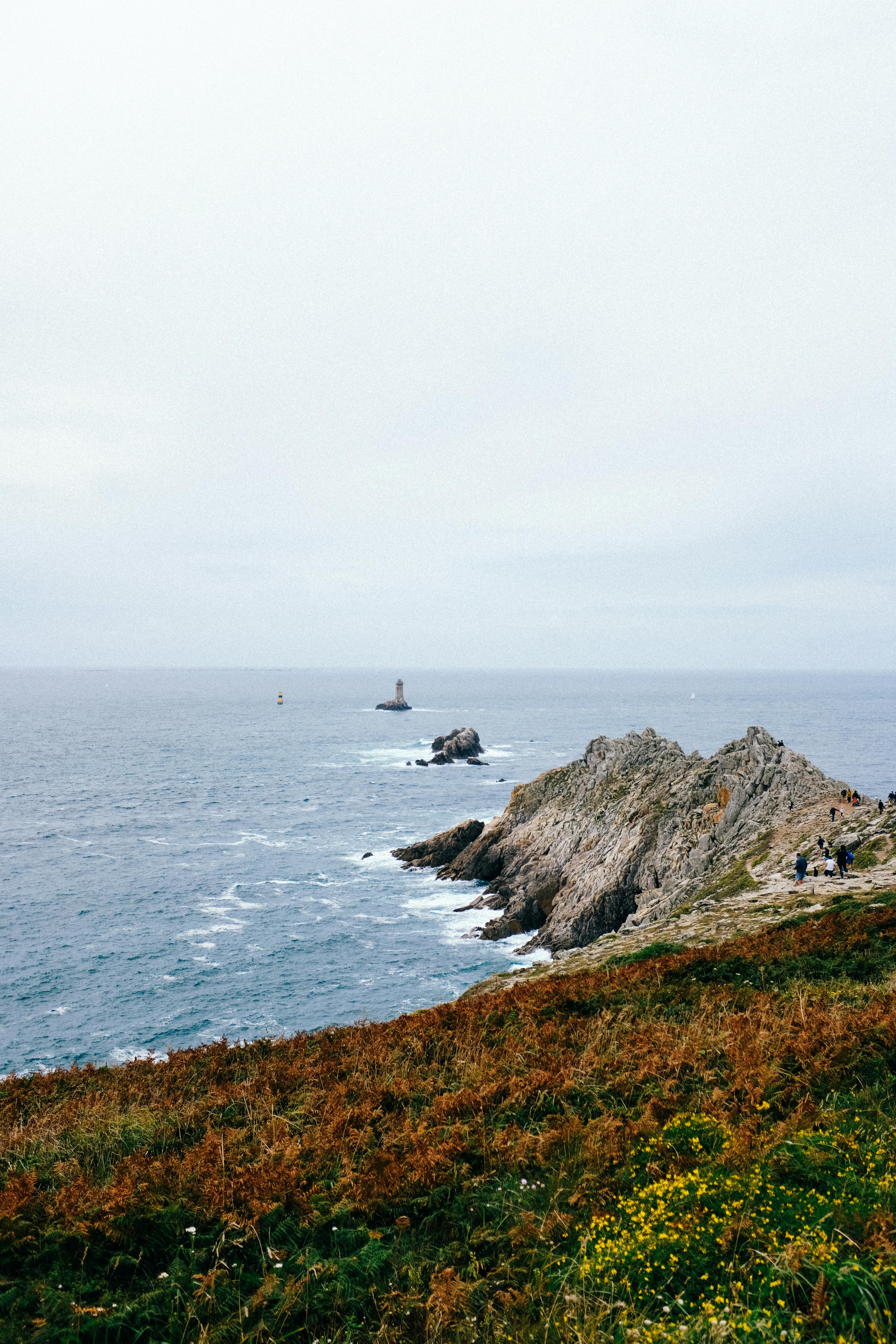 Gray Rock Formation on Sea under White Sky · Free Stock Photo