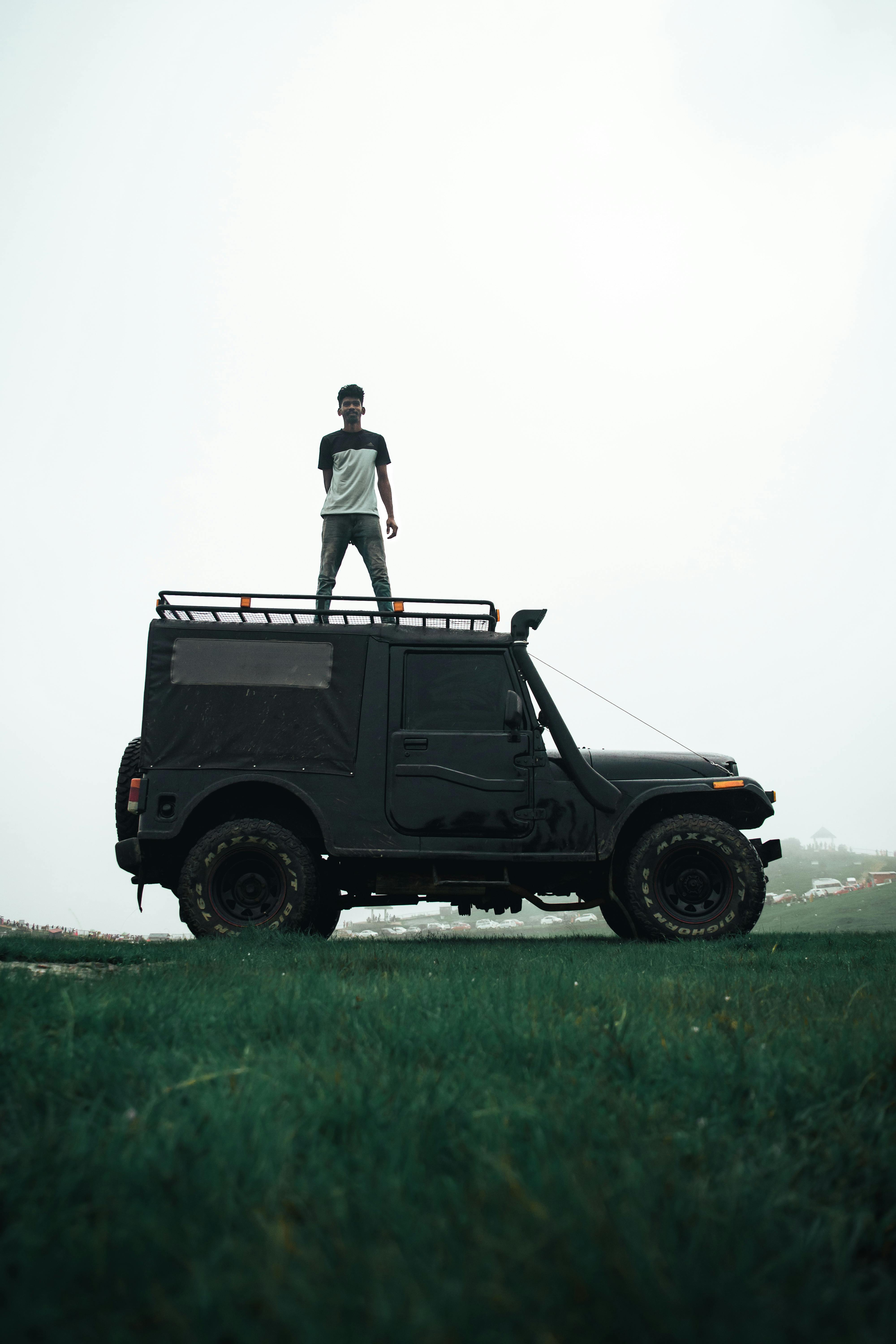 A Man Standing on Top of a Parked Car · Free Stock Photo