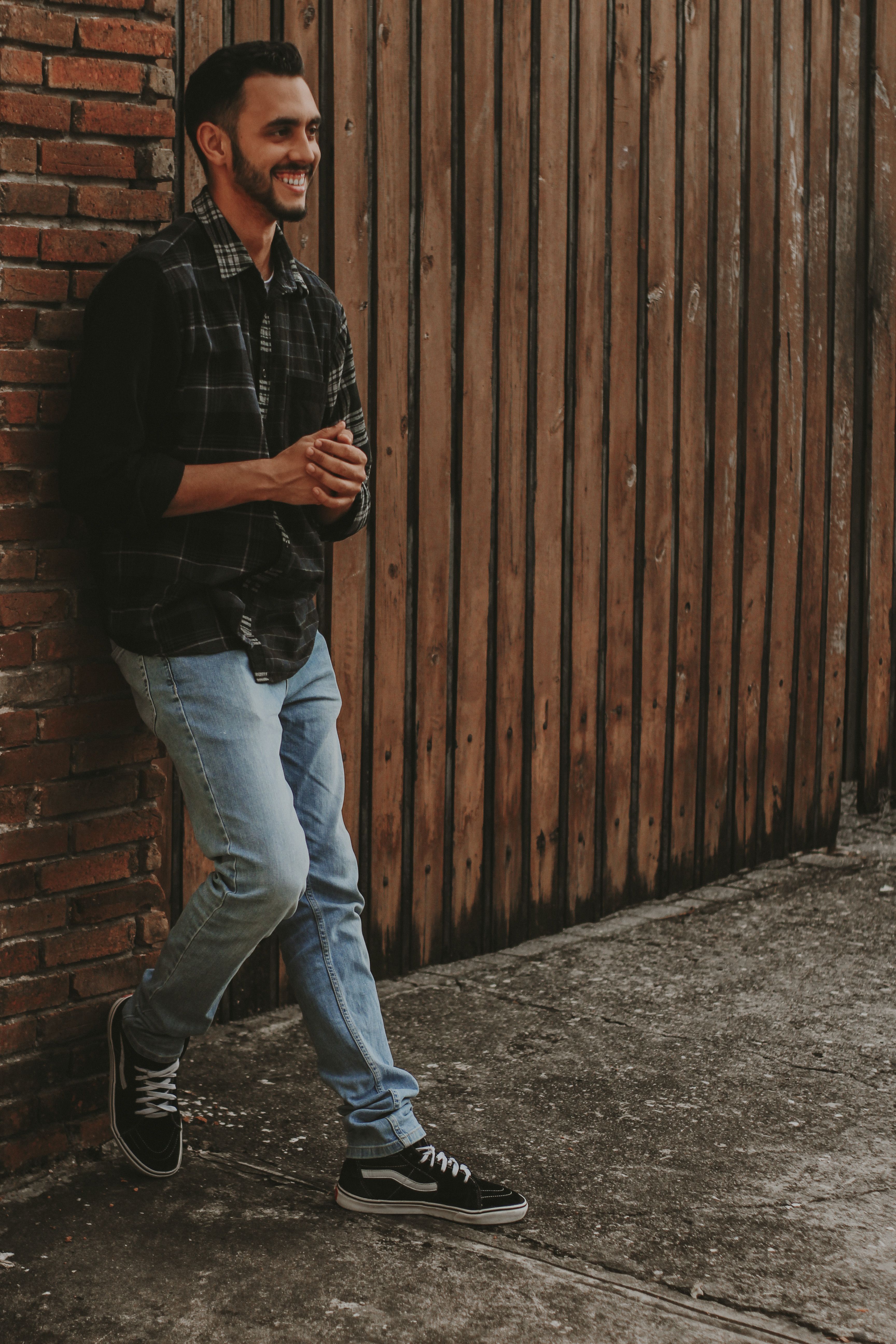 A Man Standing while Leaning on a Brick Wall · Free Stock Photo