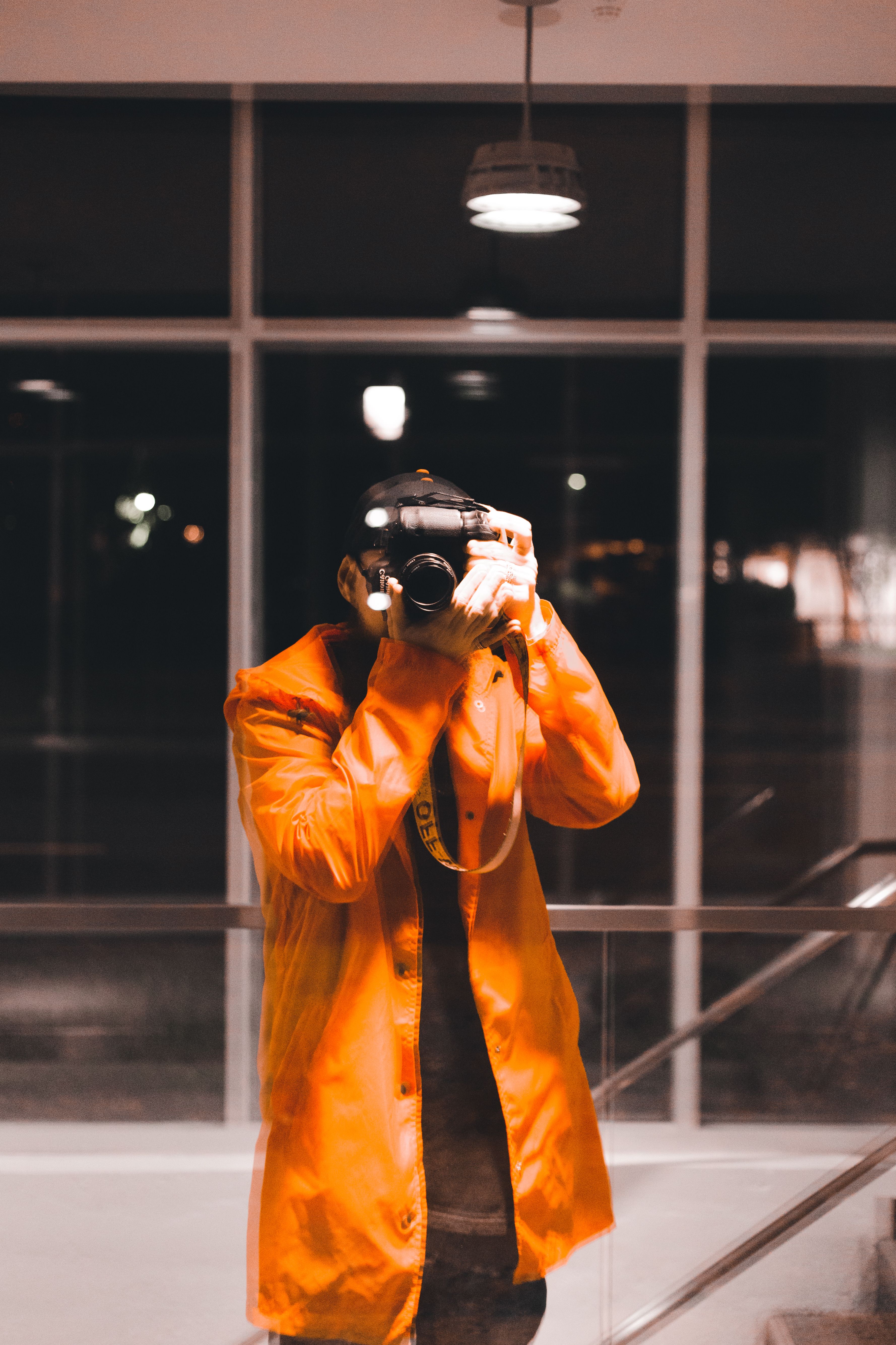 A Person in Orange Jacket while Holding a Camera · Free Stock Photo