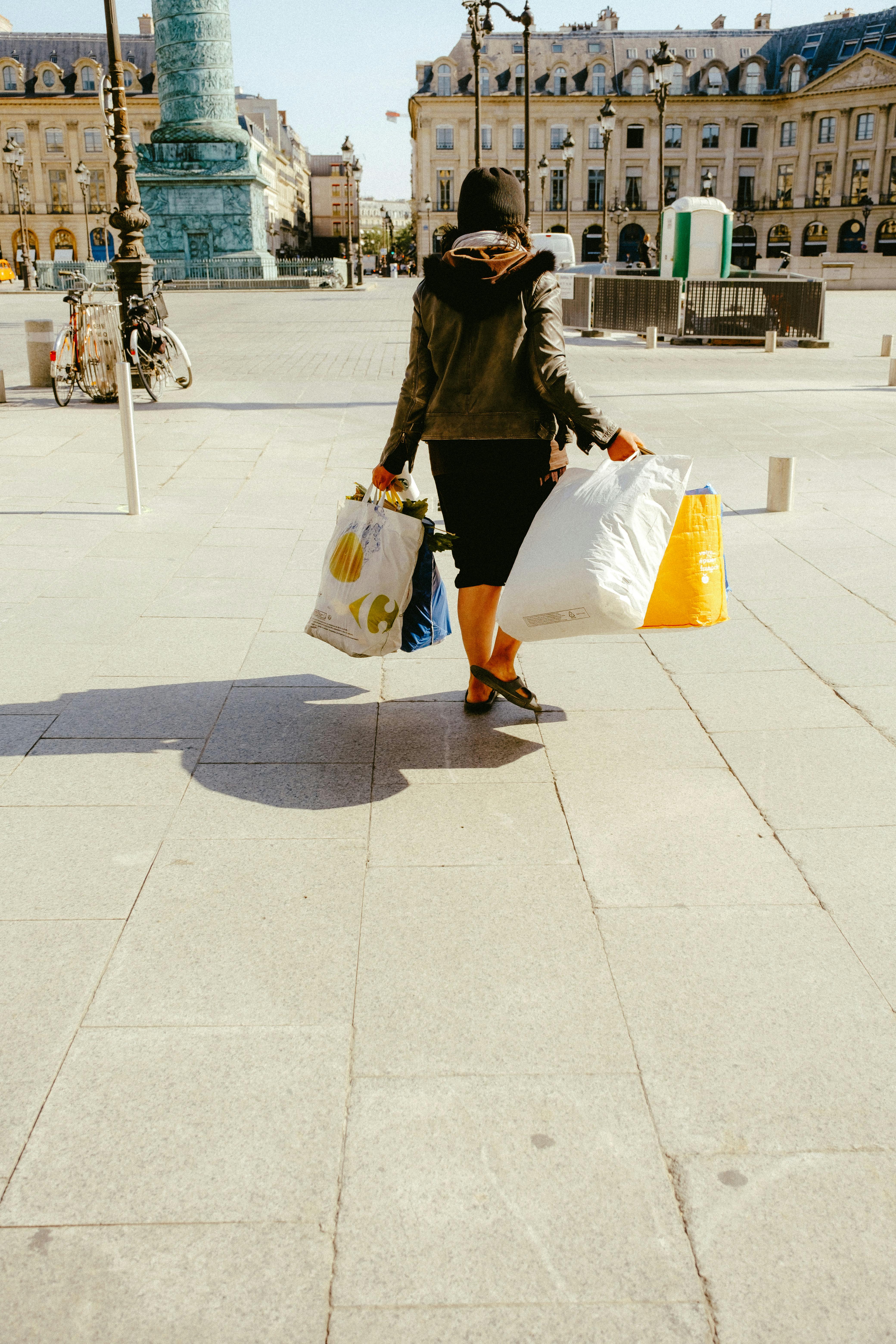 A Back View of a Person Walking while Carrying Shopping Bags · Free ...