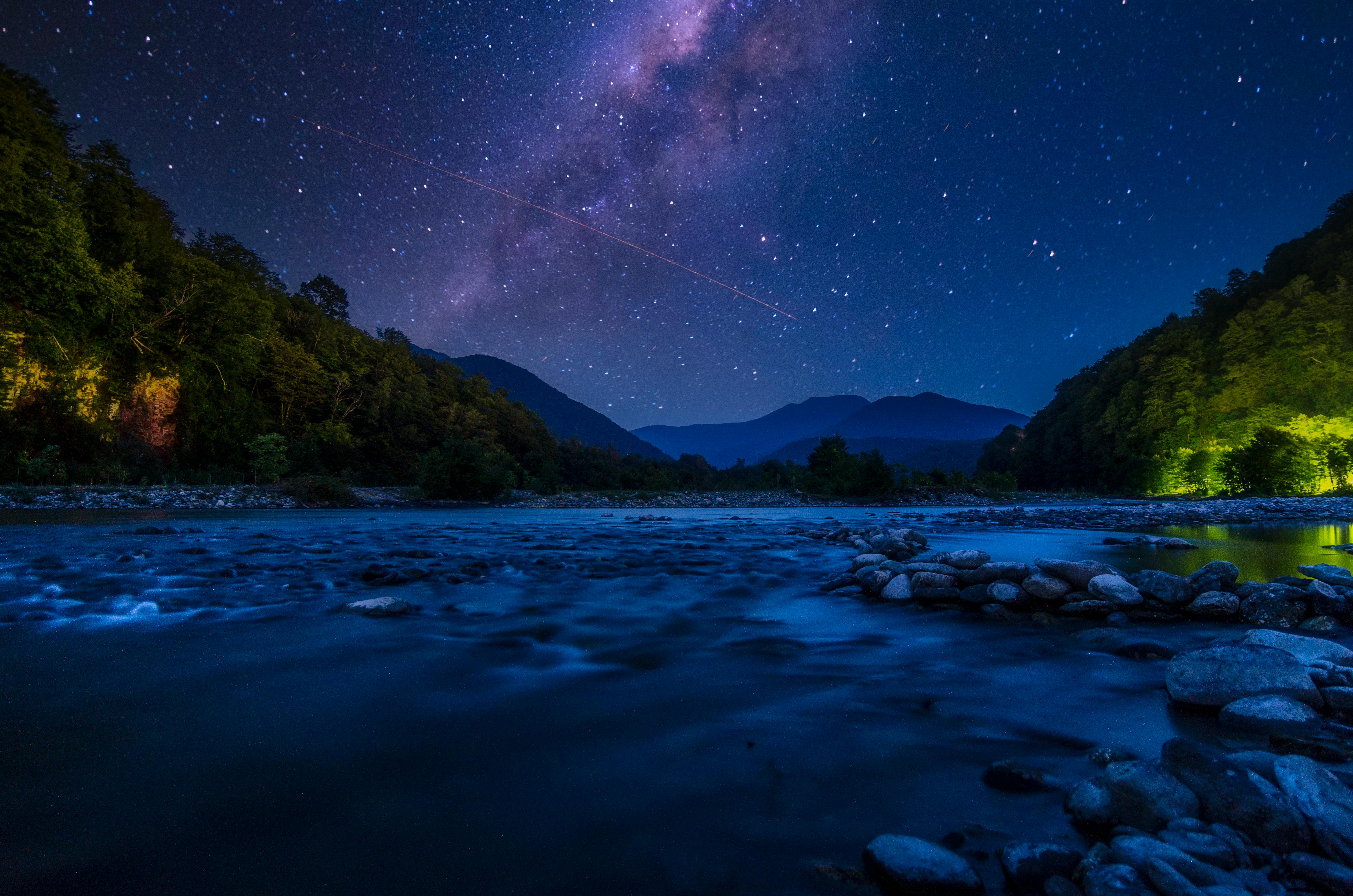 Body of Water Near Green Mountains During Night Time · Free Stock Photo