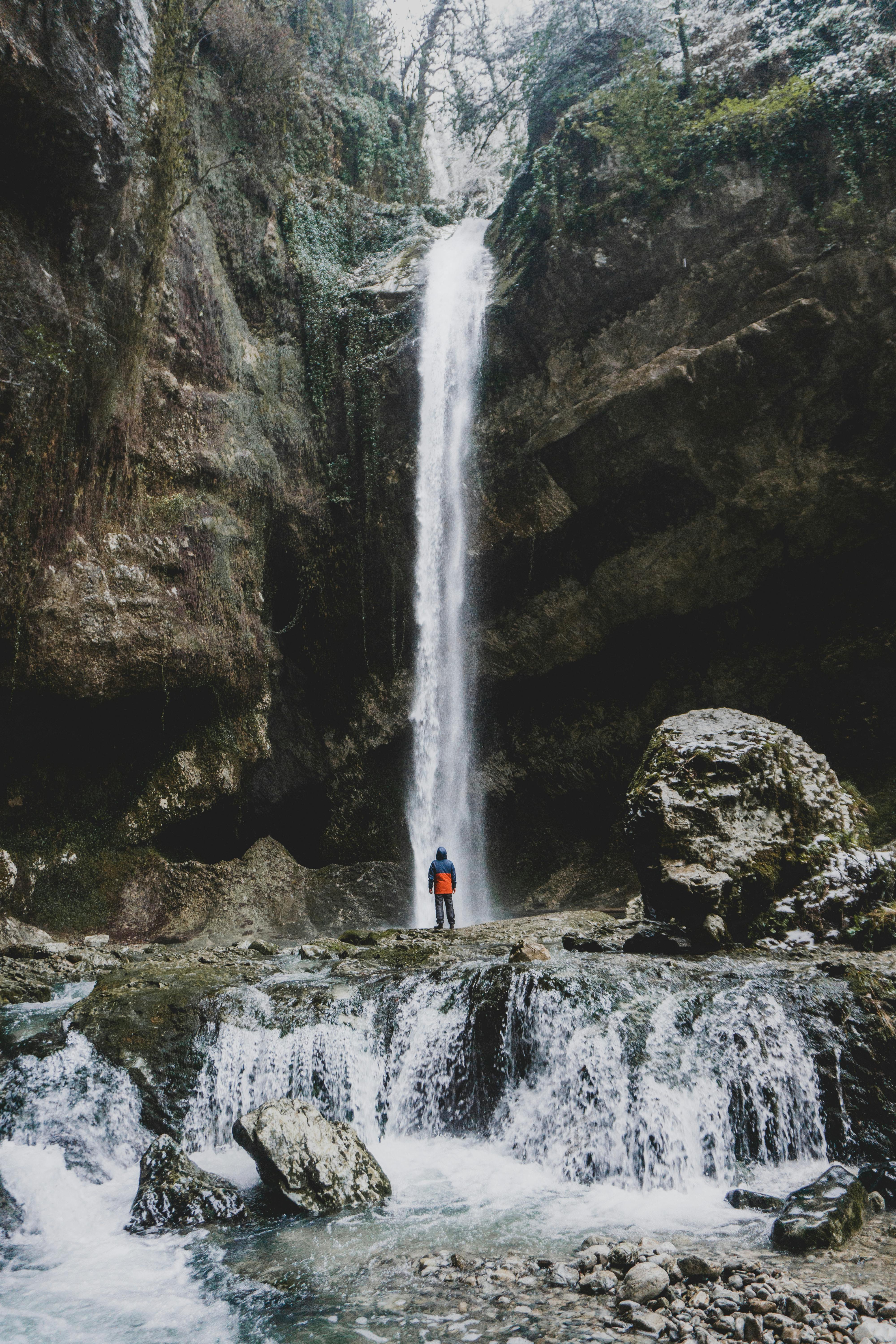 Person Standing Under a Waterfalls · Free Stock Photo