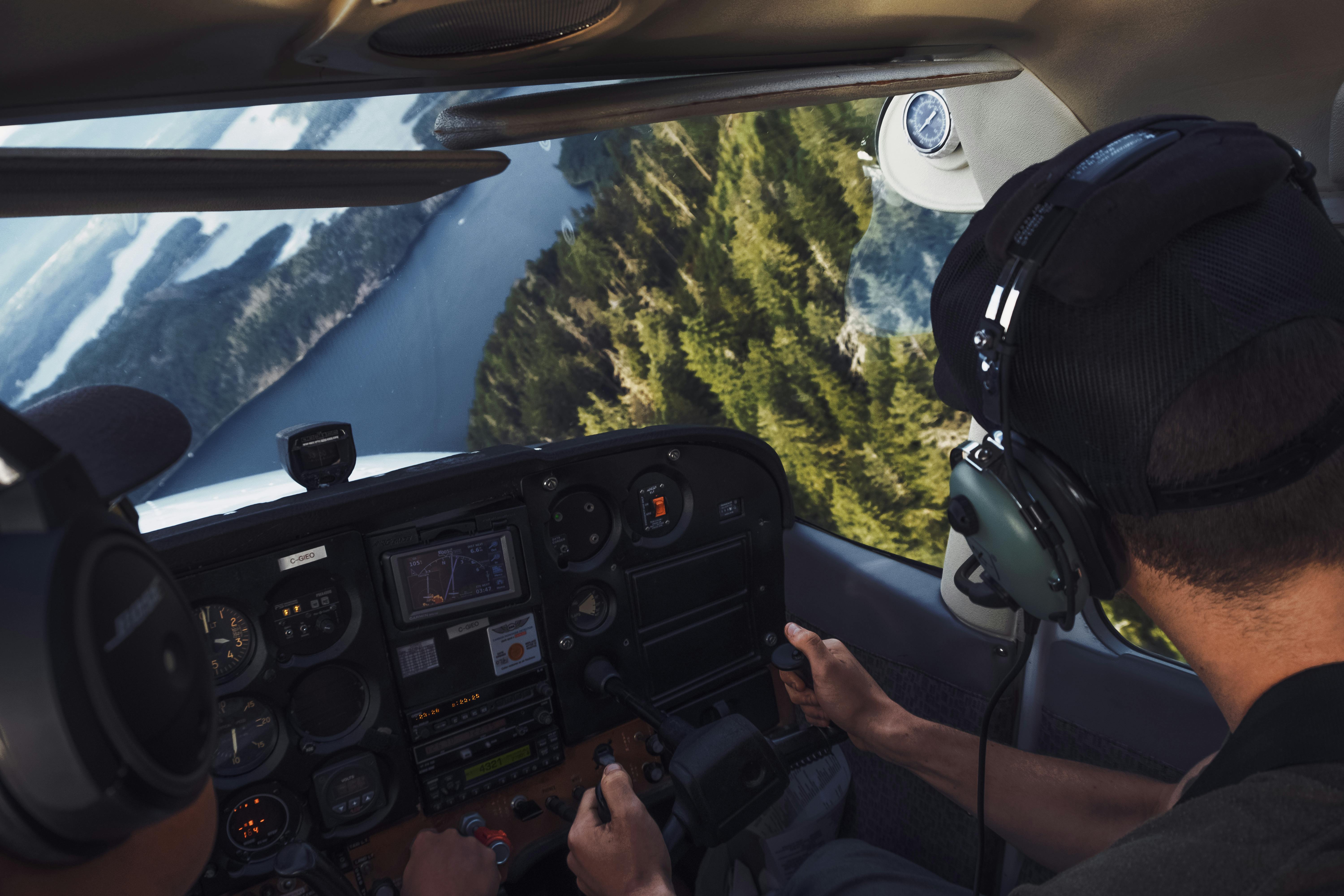 Pilots in a Plane Flying Over a River and Trees · Free Stock Photo