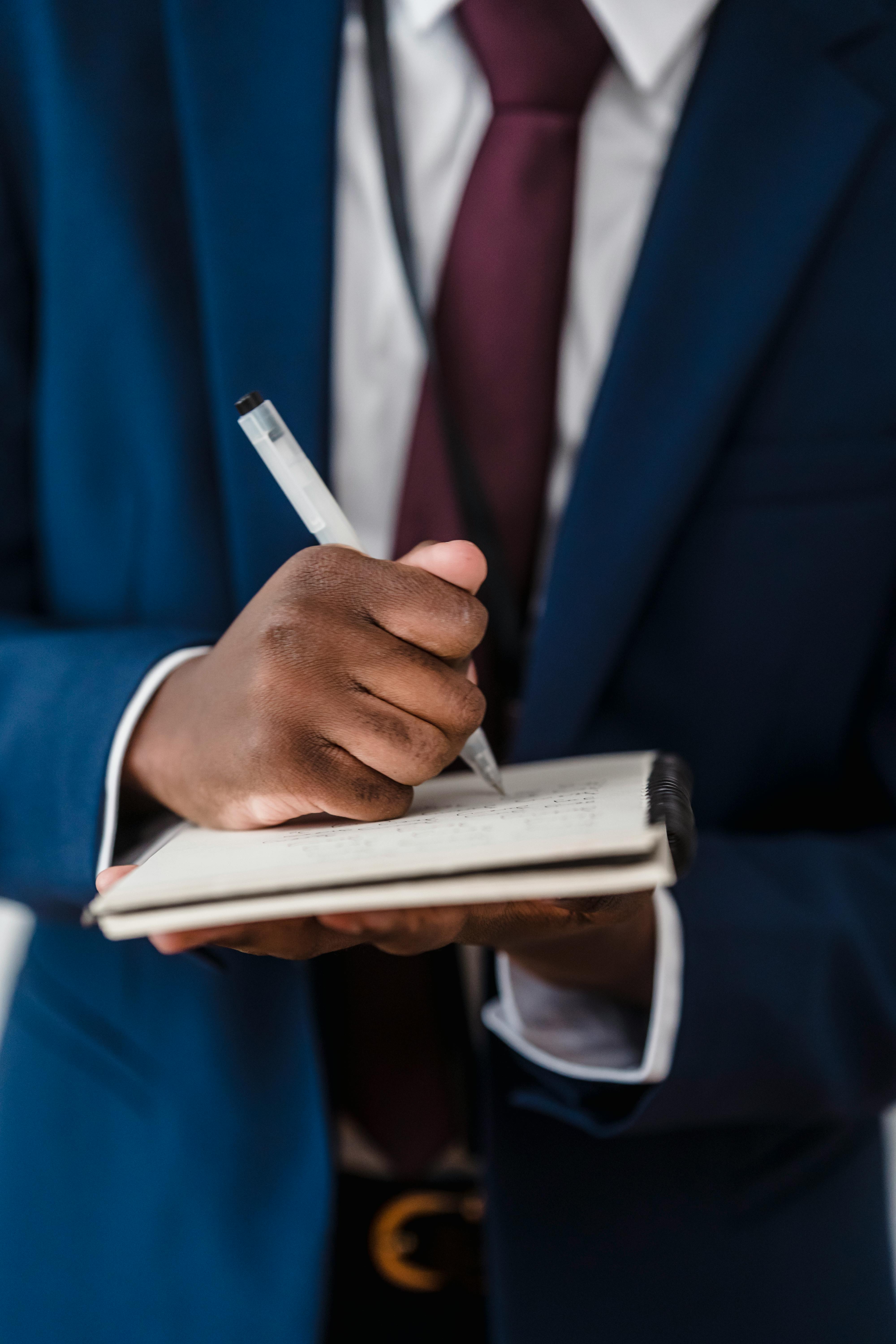Person in Blue Suit Writing on Notebook · Free Stock Photo