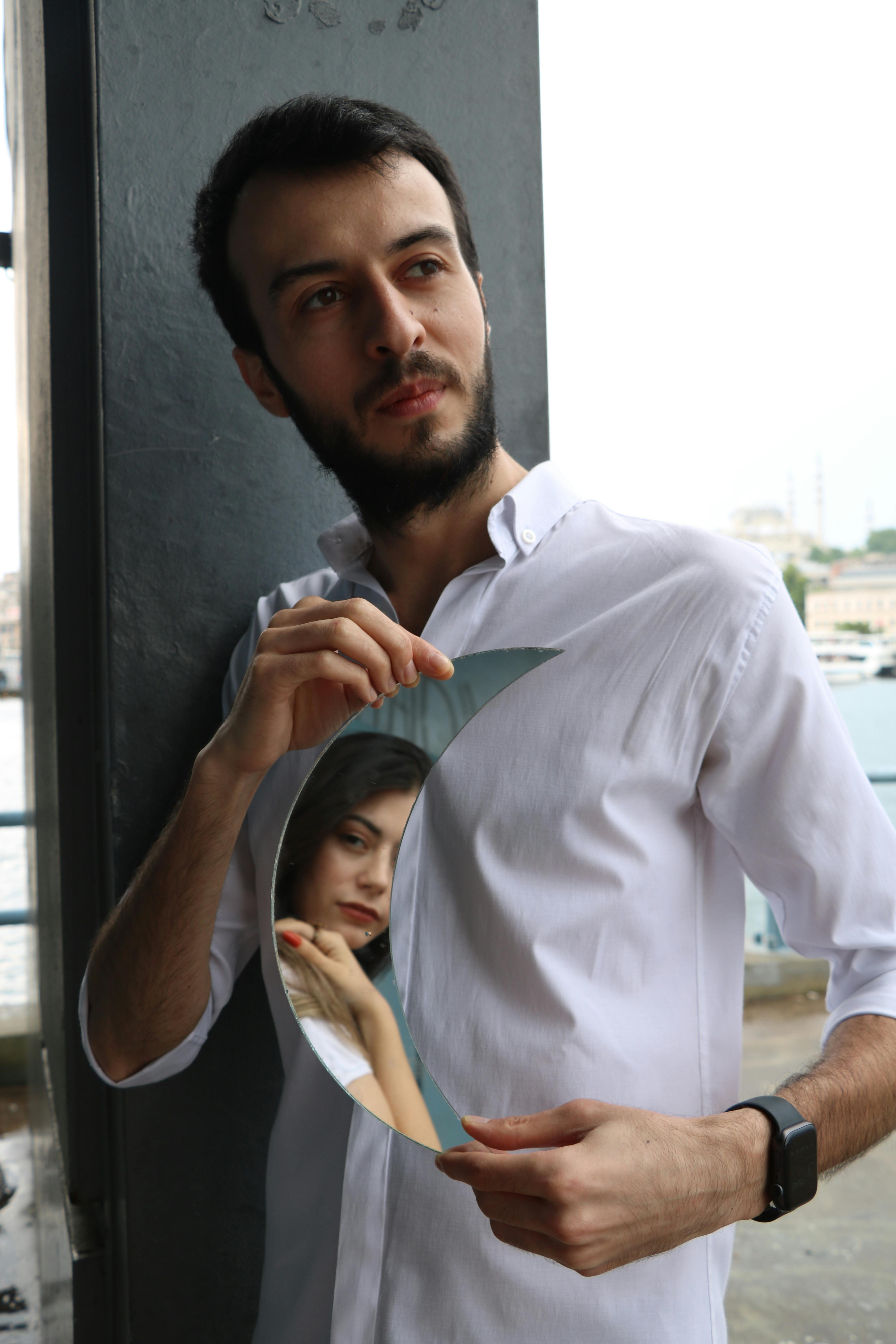Man Holding a Mirror in the Shape of Crescent Moon · Free Stock Photo