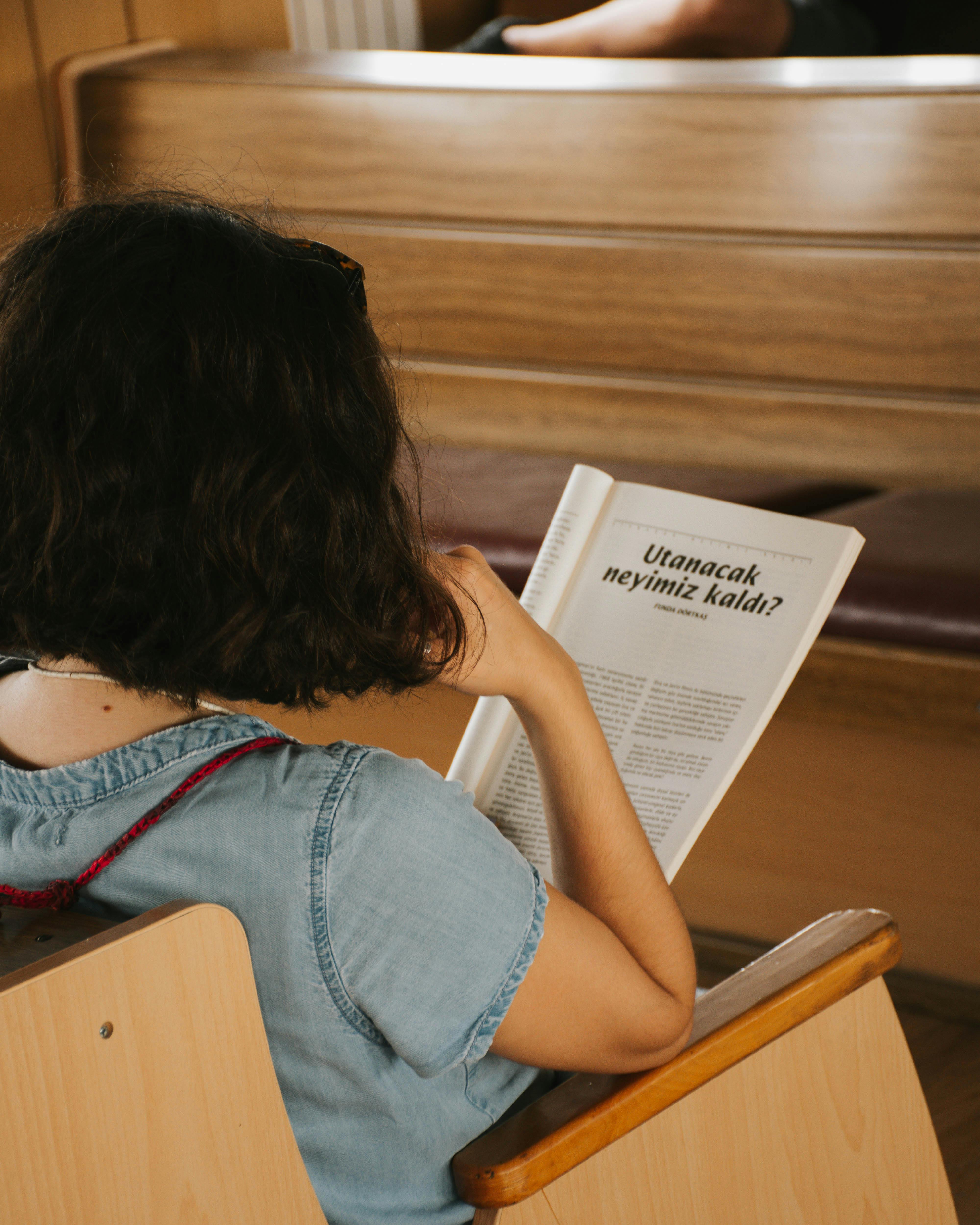 A Woman Sitting While Reading a Book · Free Stock Photo