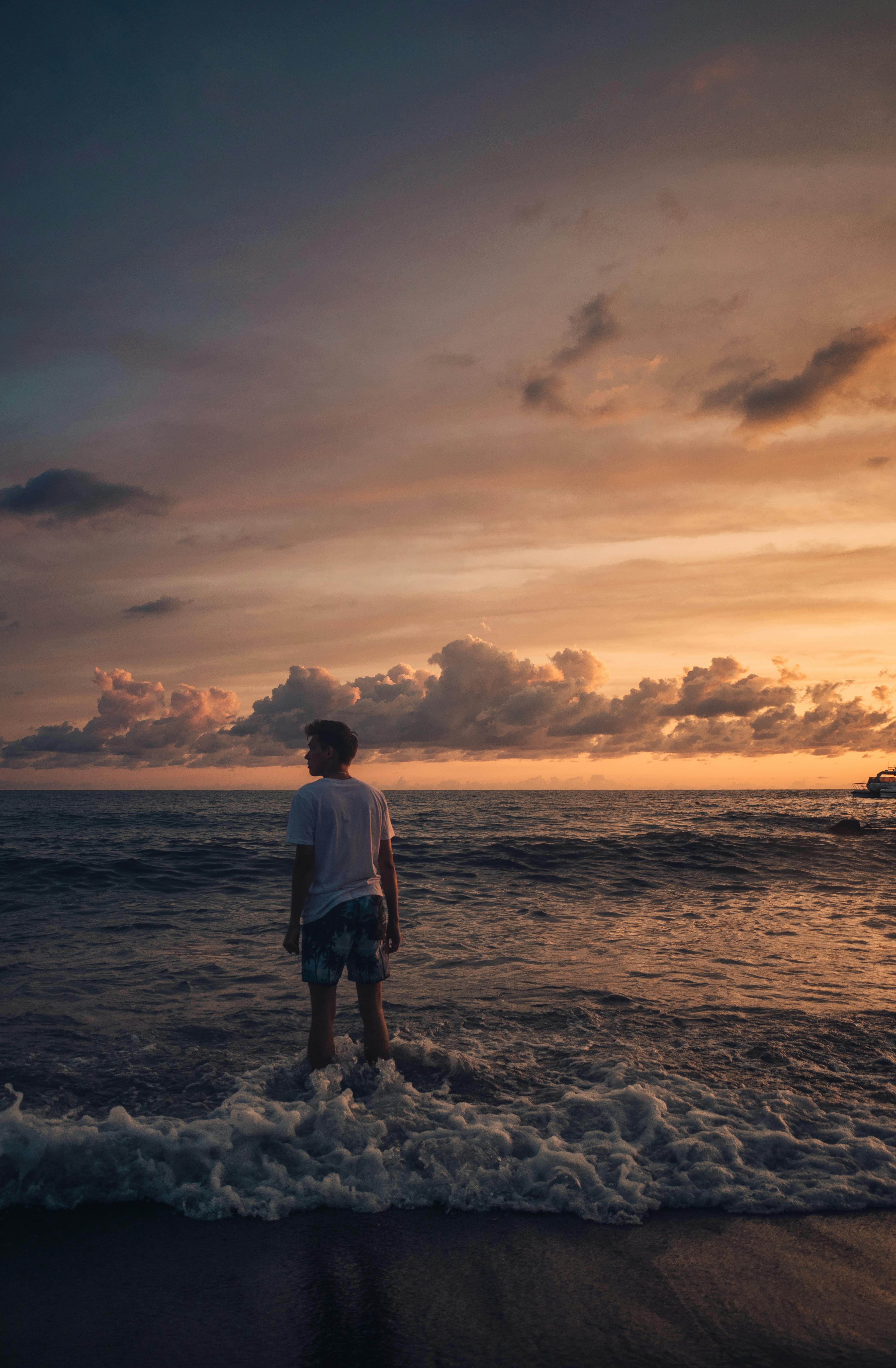 Man Standing Next to People Seated on Benches · Free Stock Photo