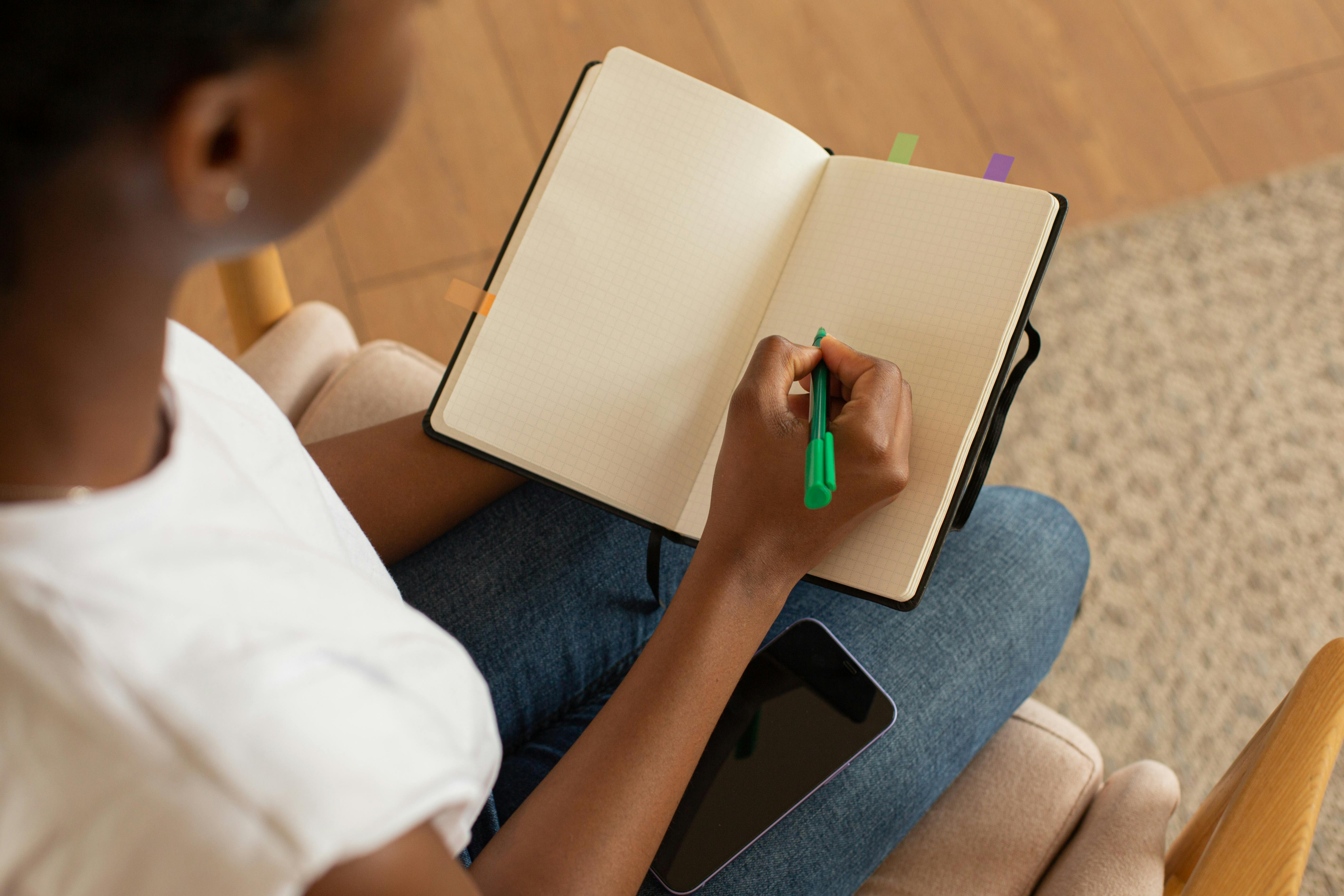 Person Holding a Notebook and a Green Pen · Free Stock Photo