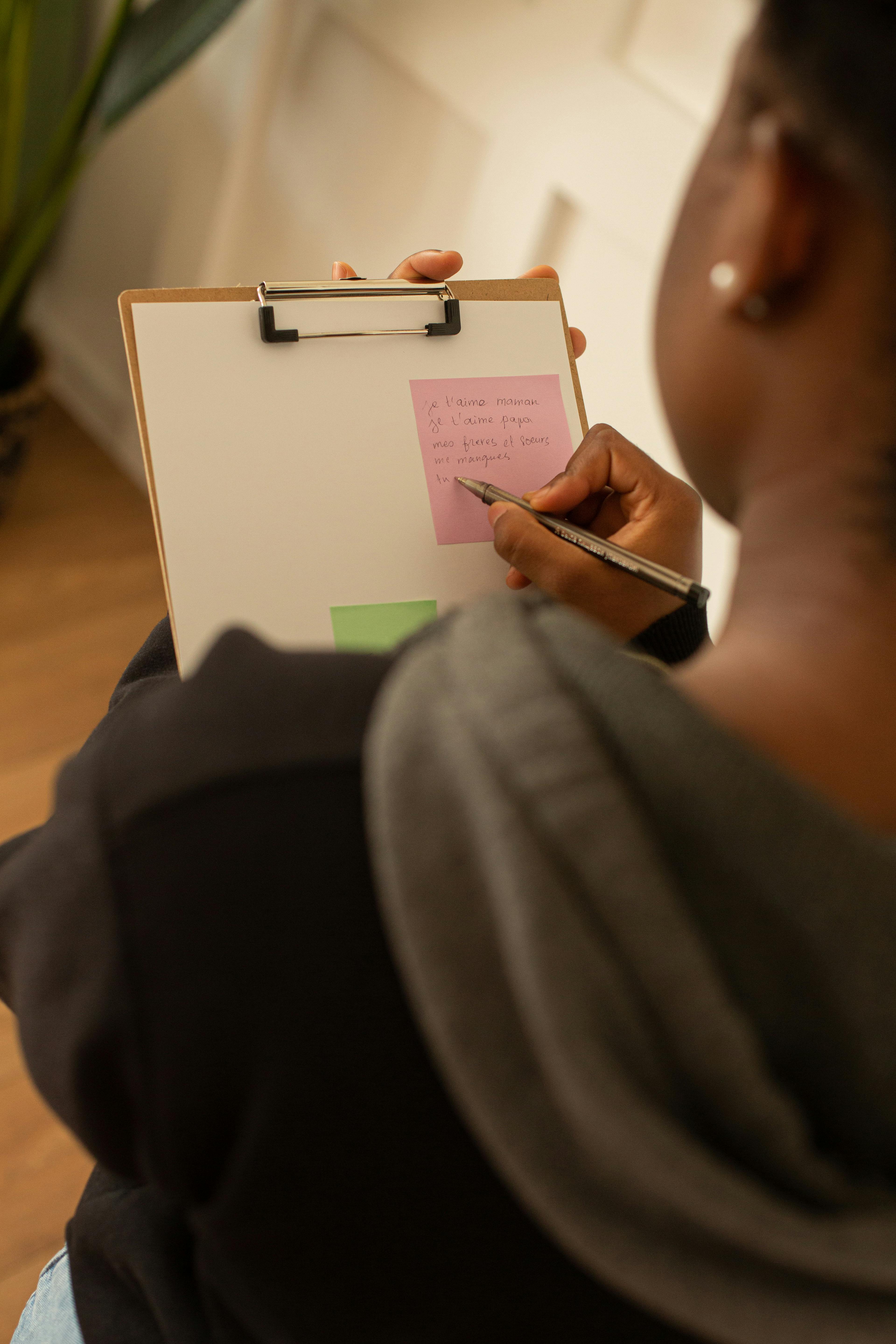 Person writing notes on Sticky Note · Free Stock Photo