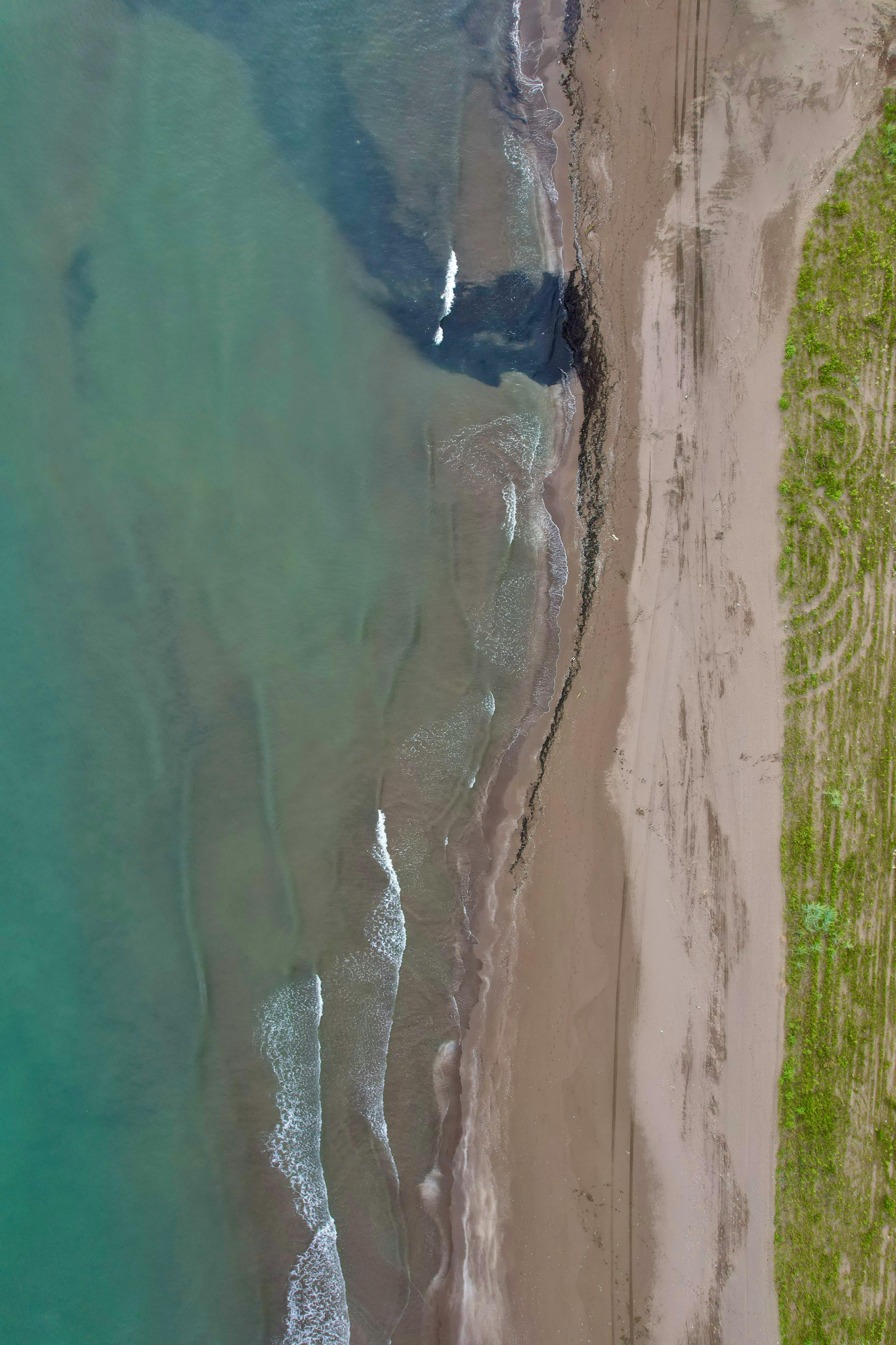 Drone Shot of Two People Walking at the Beach · Free Stock Photo