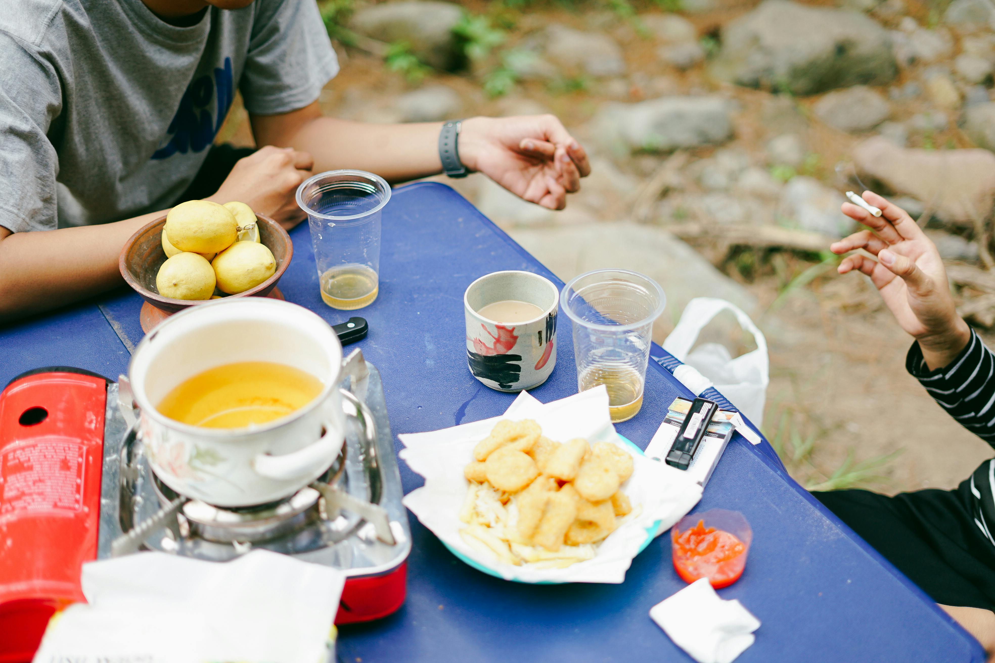 Two People Sitting by the Table with Food and Drinks · Free Stock Photo
