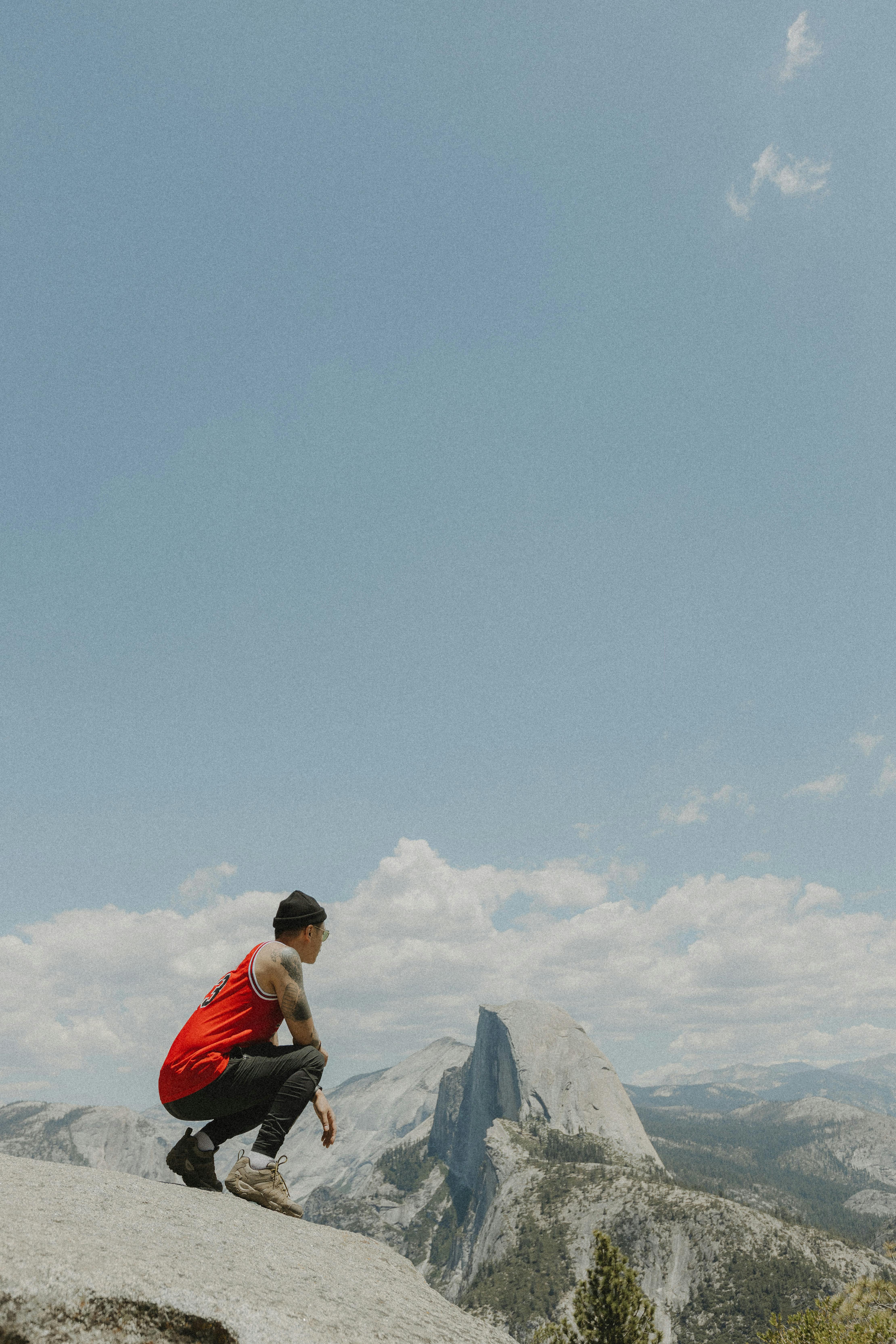 A Man Crouching while at the Edge of a Cliff · Free Stock Photo