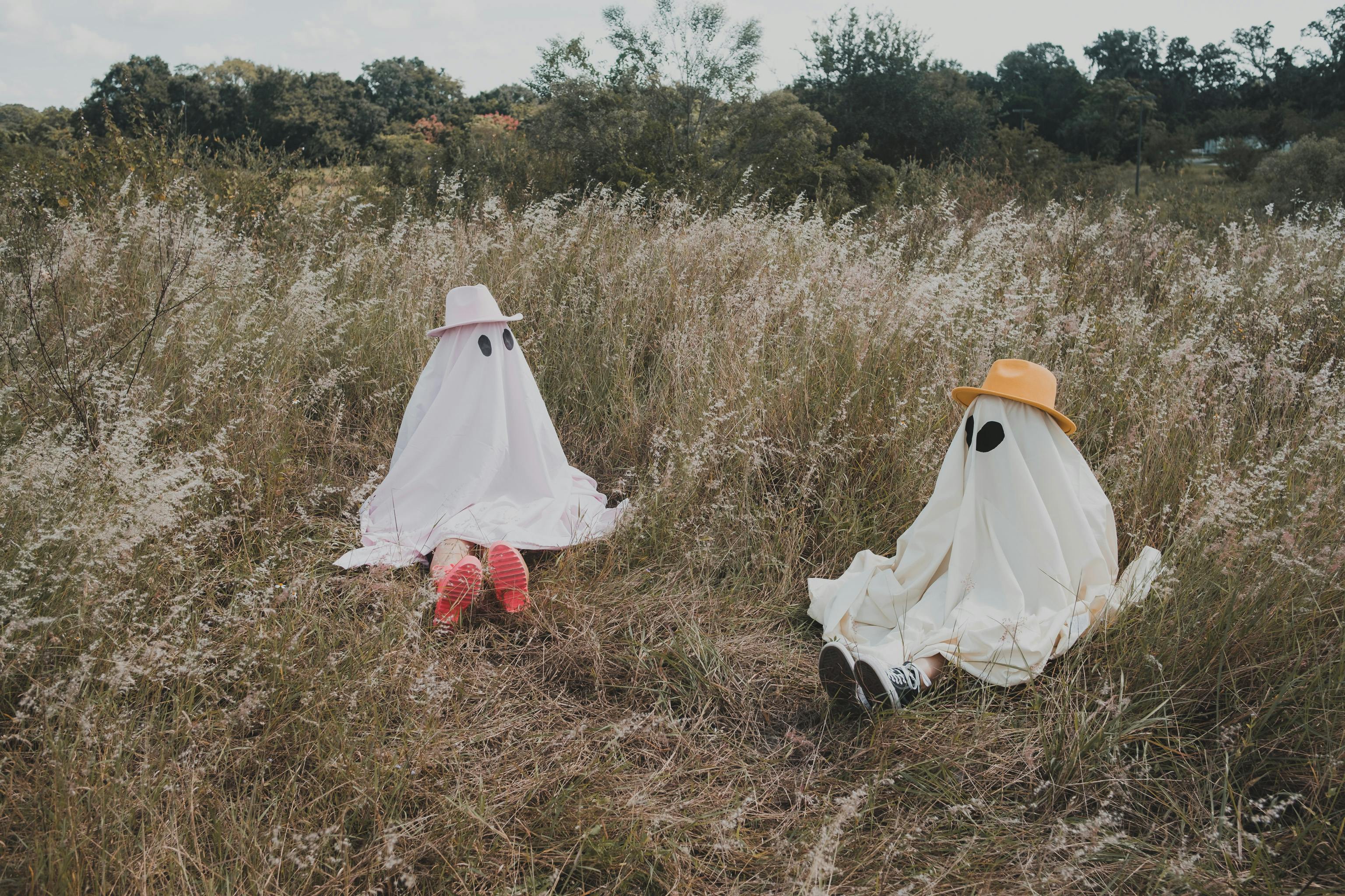 Photo of People in Ghost Costumes Sitting on the Grass · Free Stock Photo
