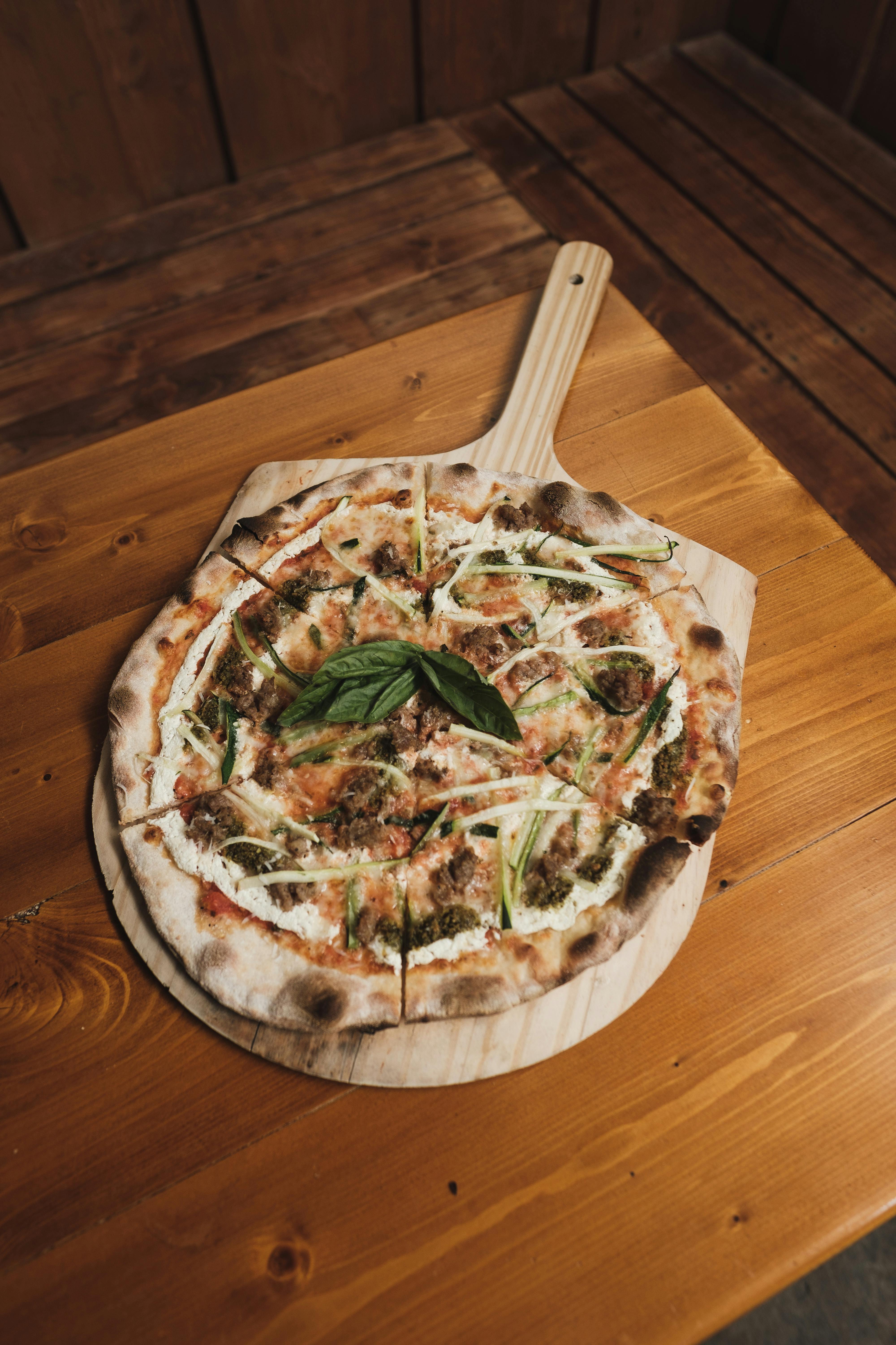 Delicious Pizza on Board on Wooden Table · Free Stock Photo