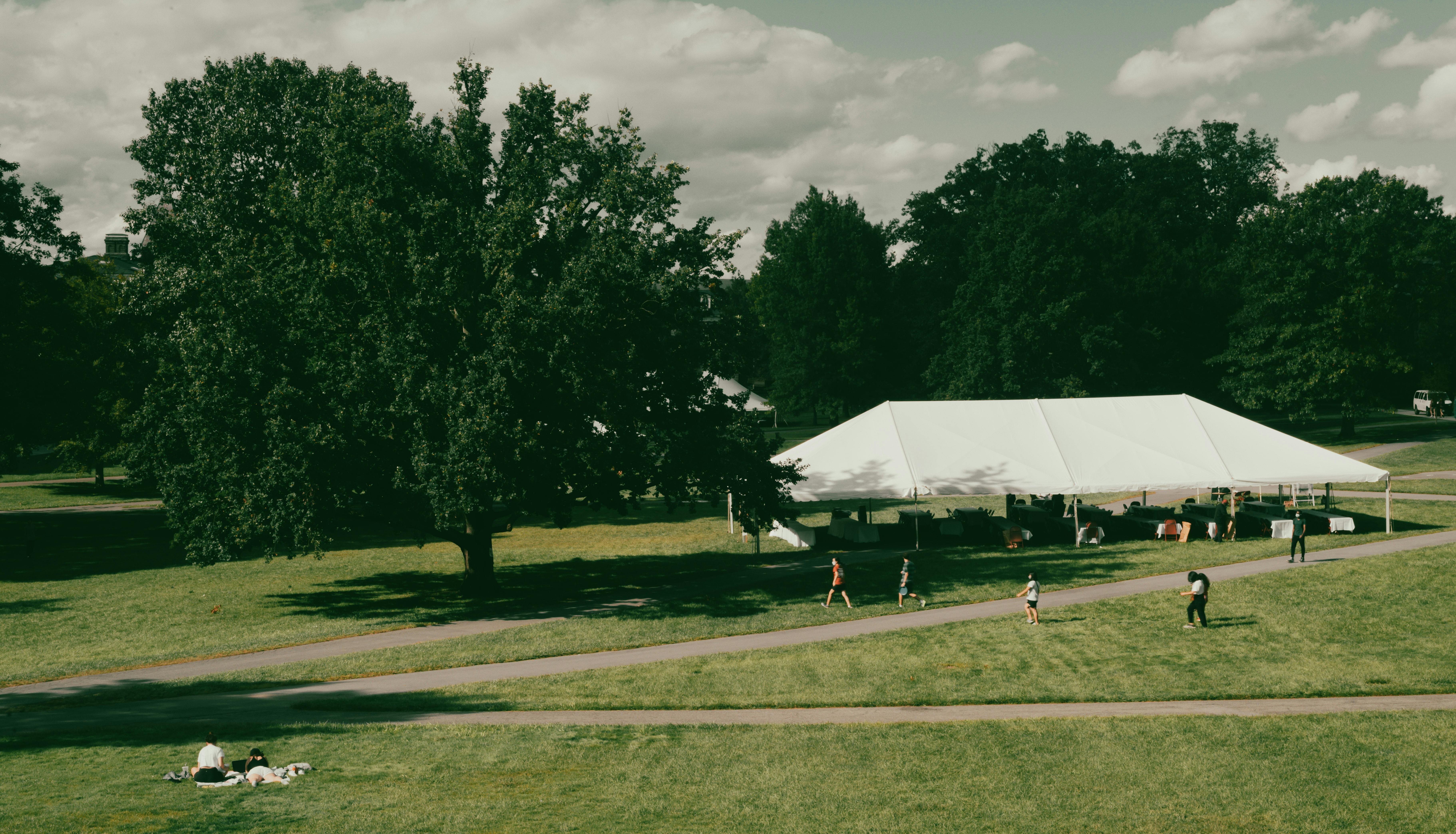People Walking on Green Grass Field Near the White Tent · Free Stock Photo