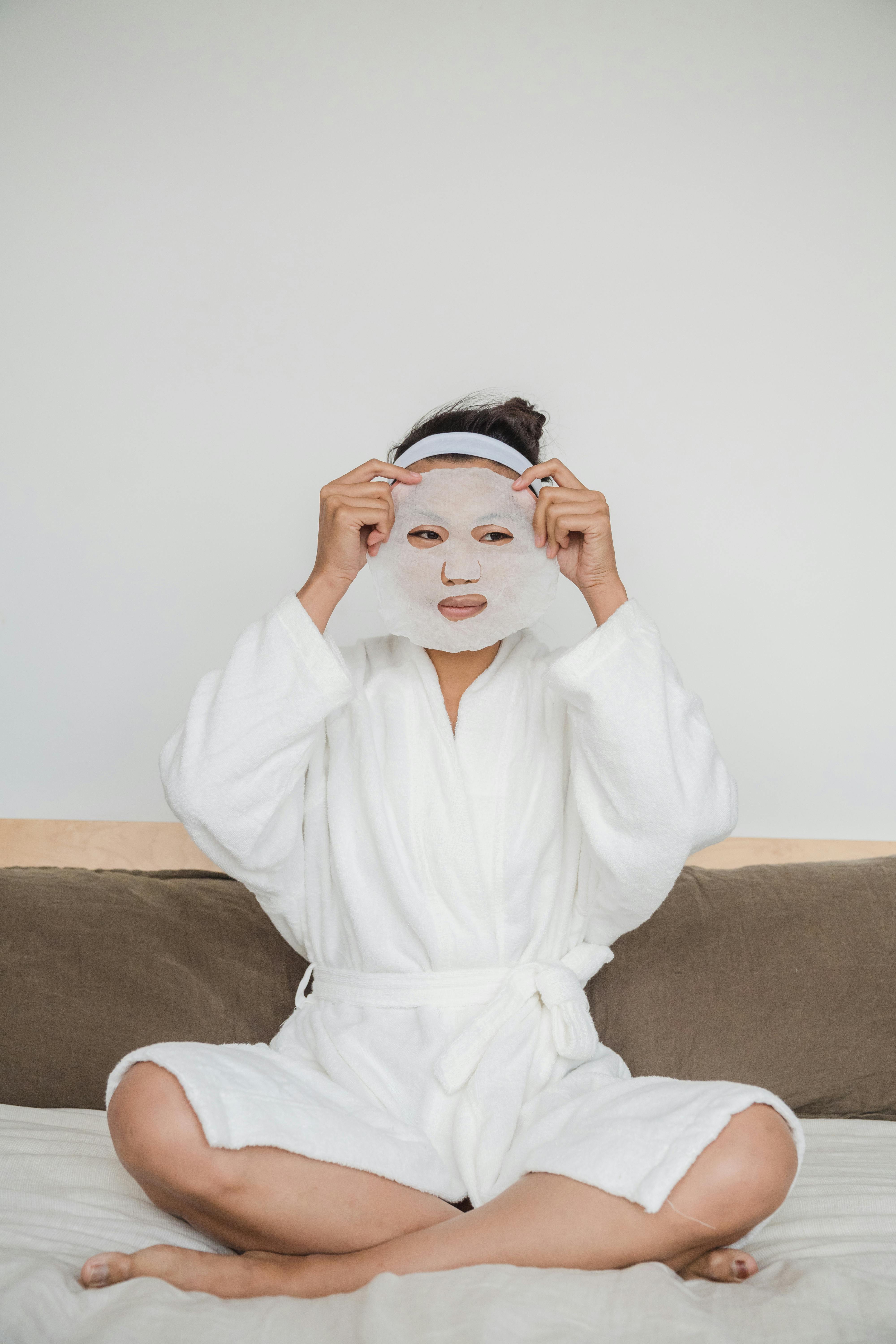 Person in White Bathrobe Putting on a Facial Mask · Free Stock Photo