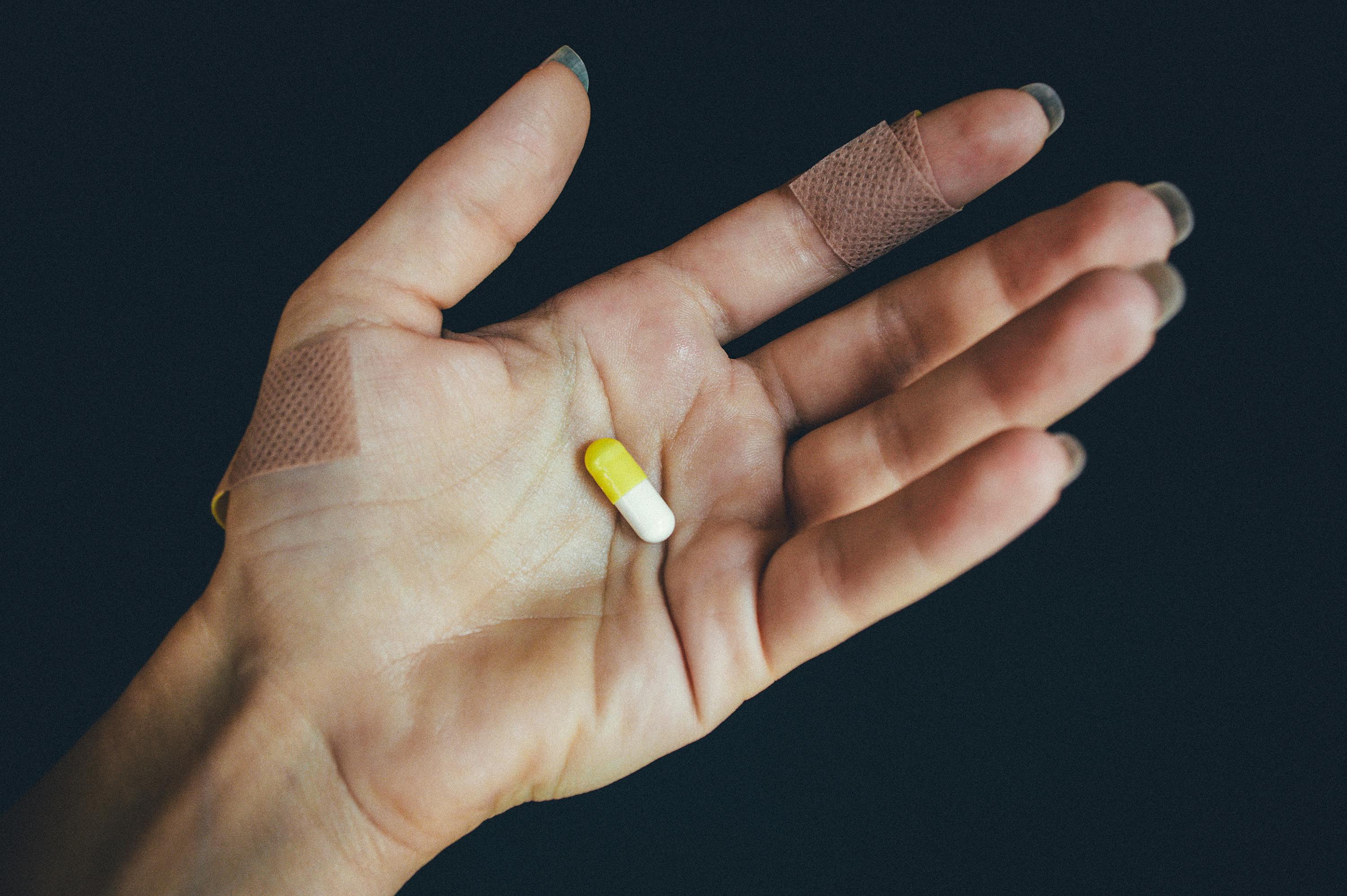 Yellow and White Capsule on the Person's Palm · Free Stock Photo