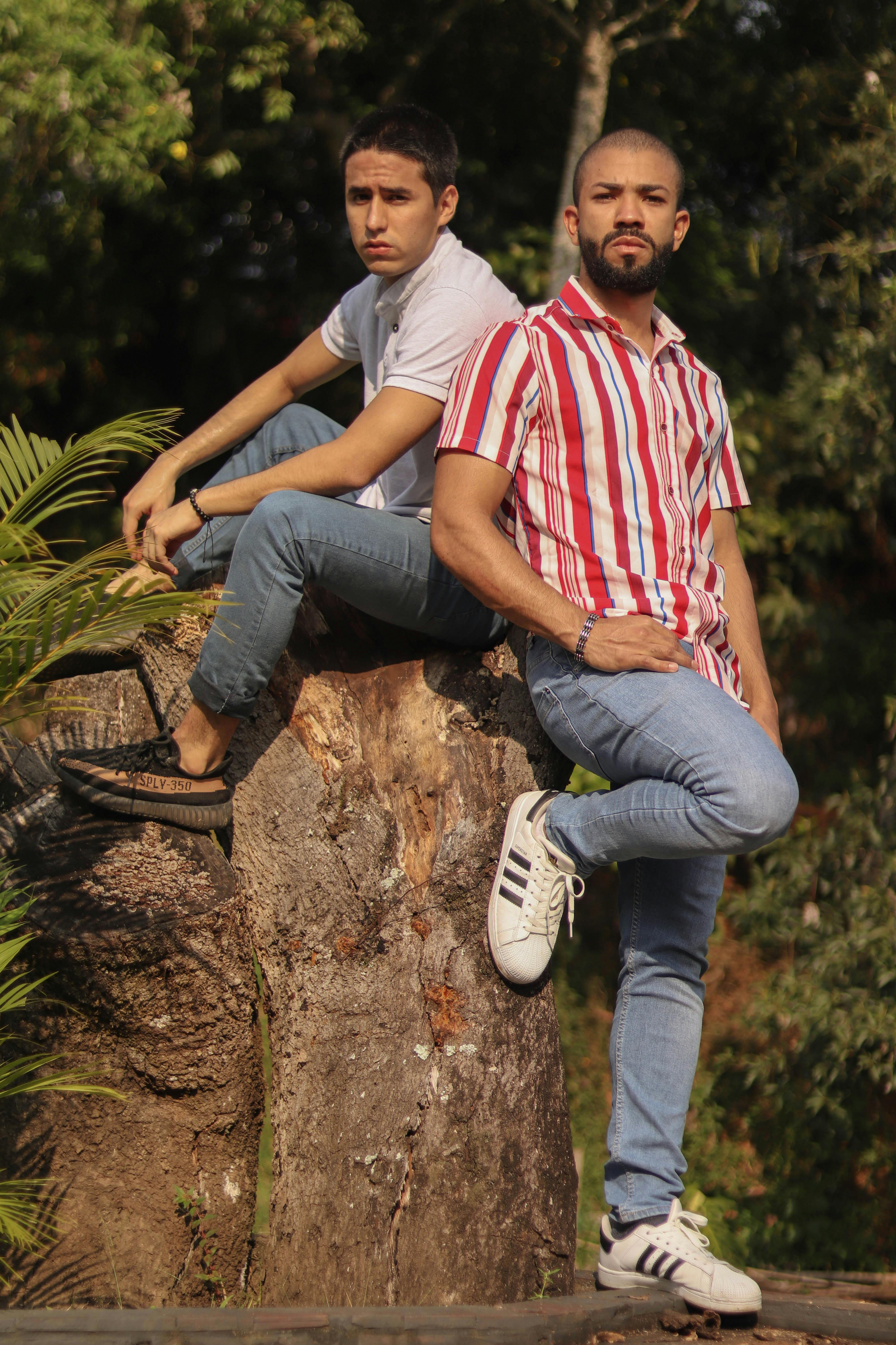 Two Men in Jeans and Shirts Posing in a Park · Free Stock Photo