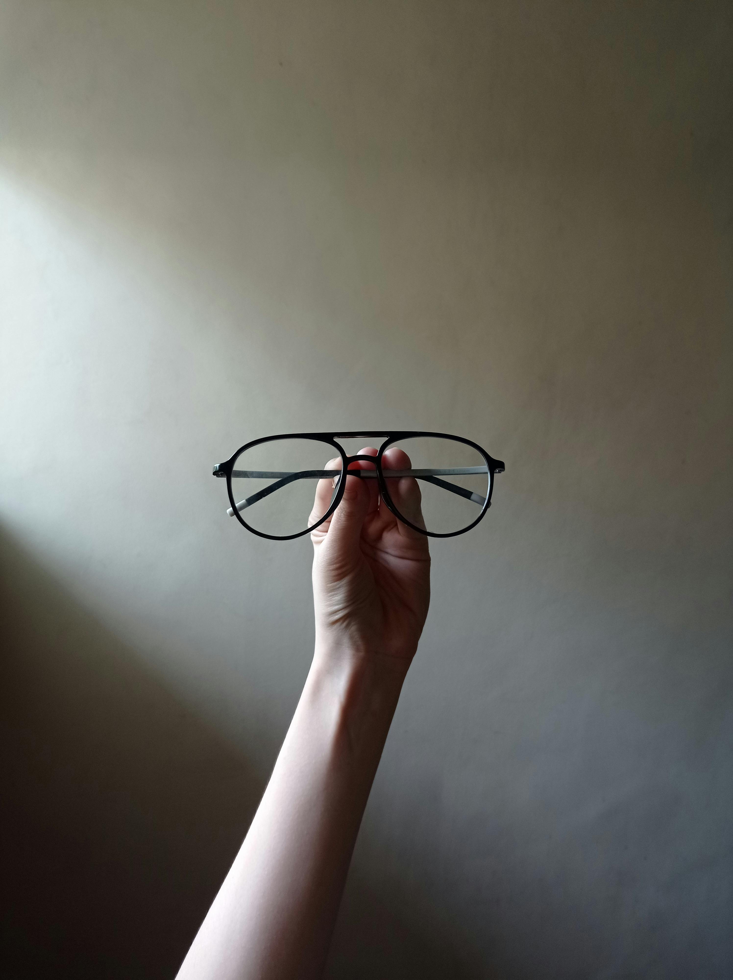 Person Holding Black Framed Eyeglasses · Free Stock Photo