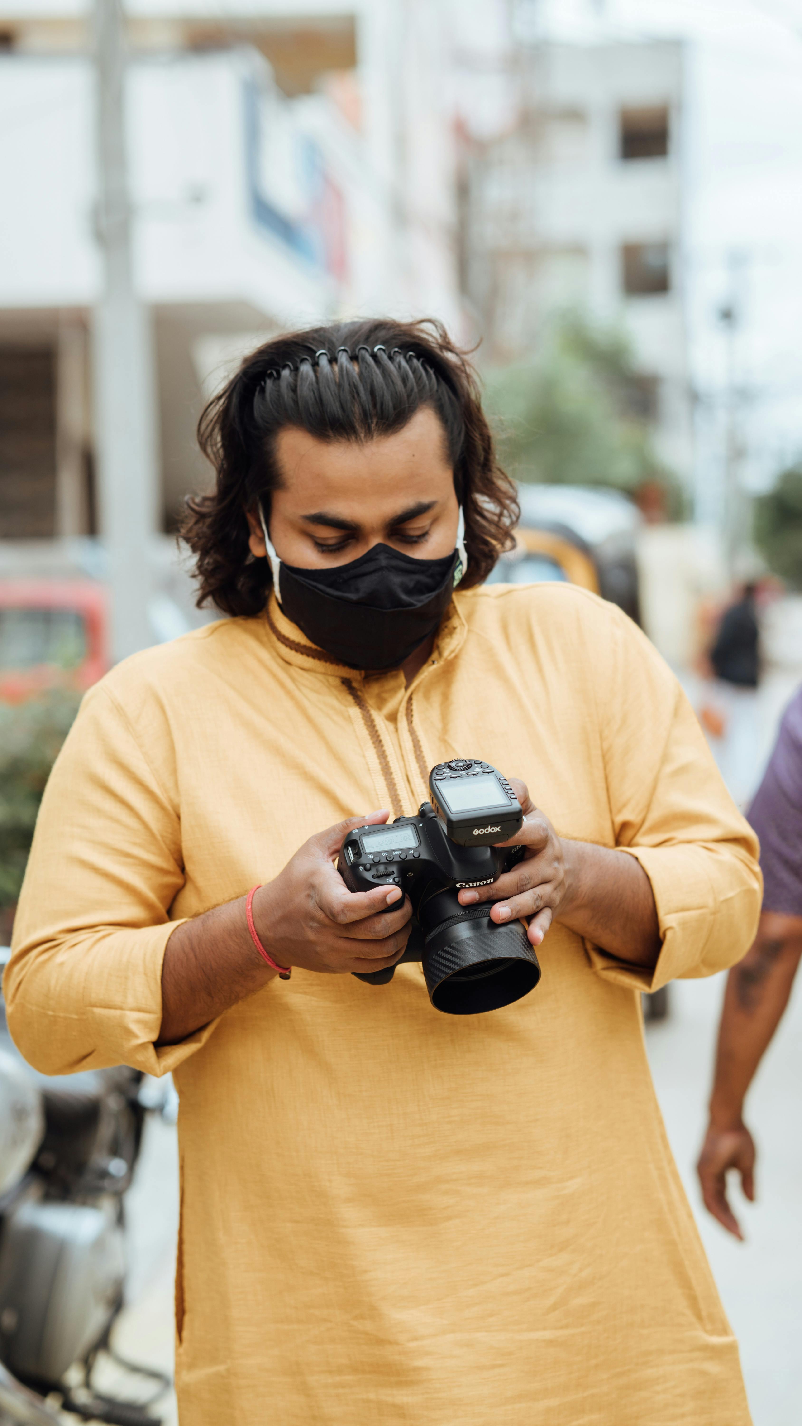 A Man in a Mask Holding a TV Set · Free Stock Photo