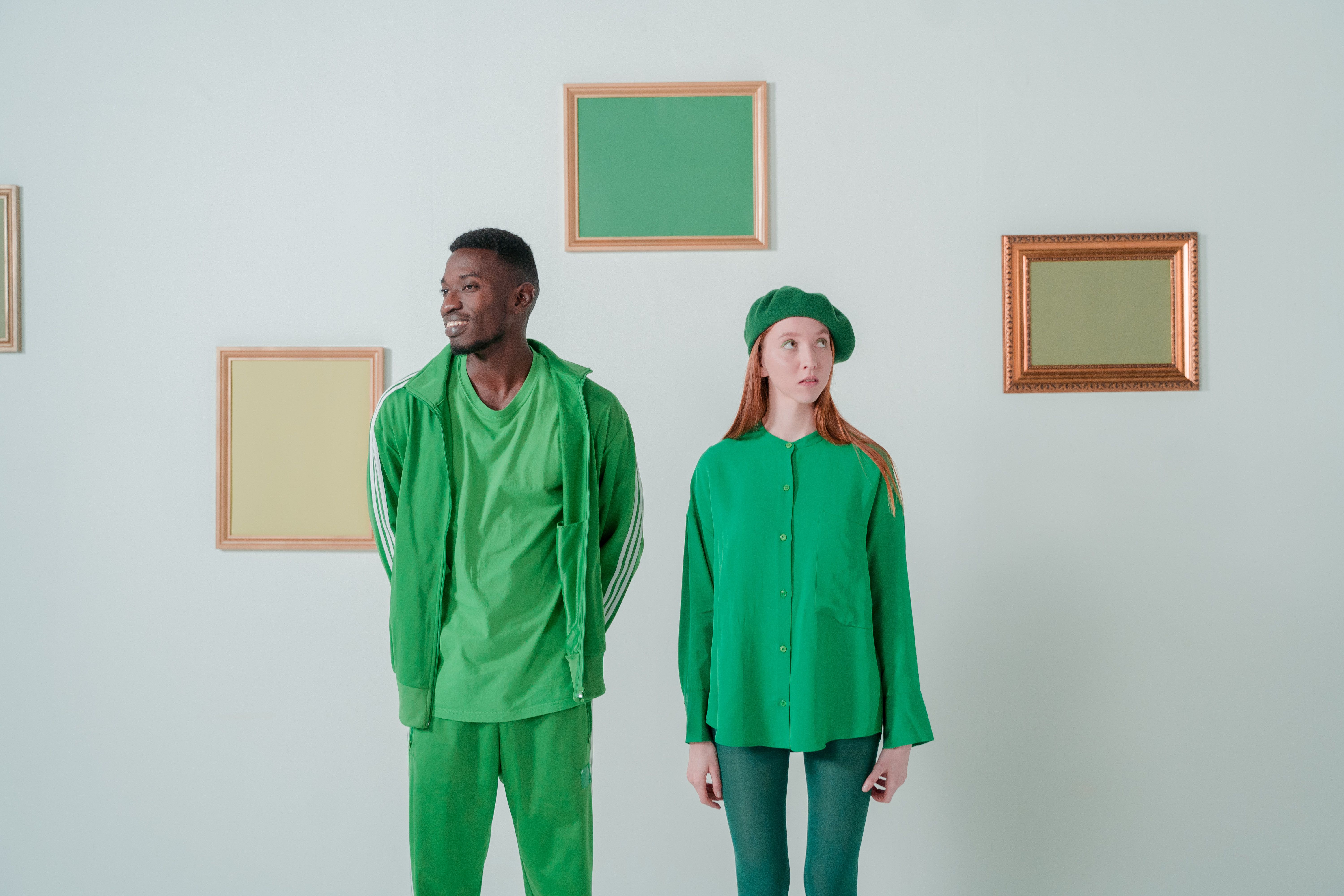 A Man and a Woman Standing beside Each Other near Frames on a Wall ...