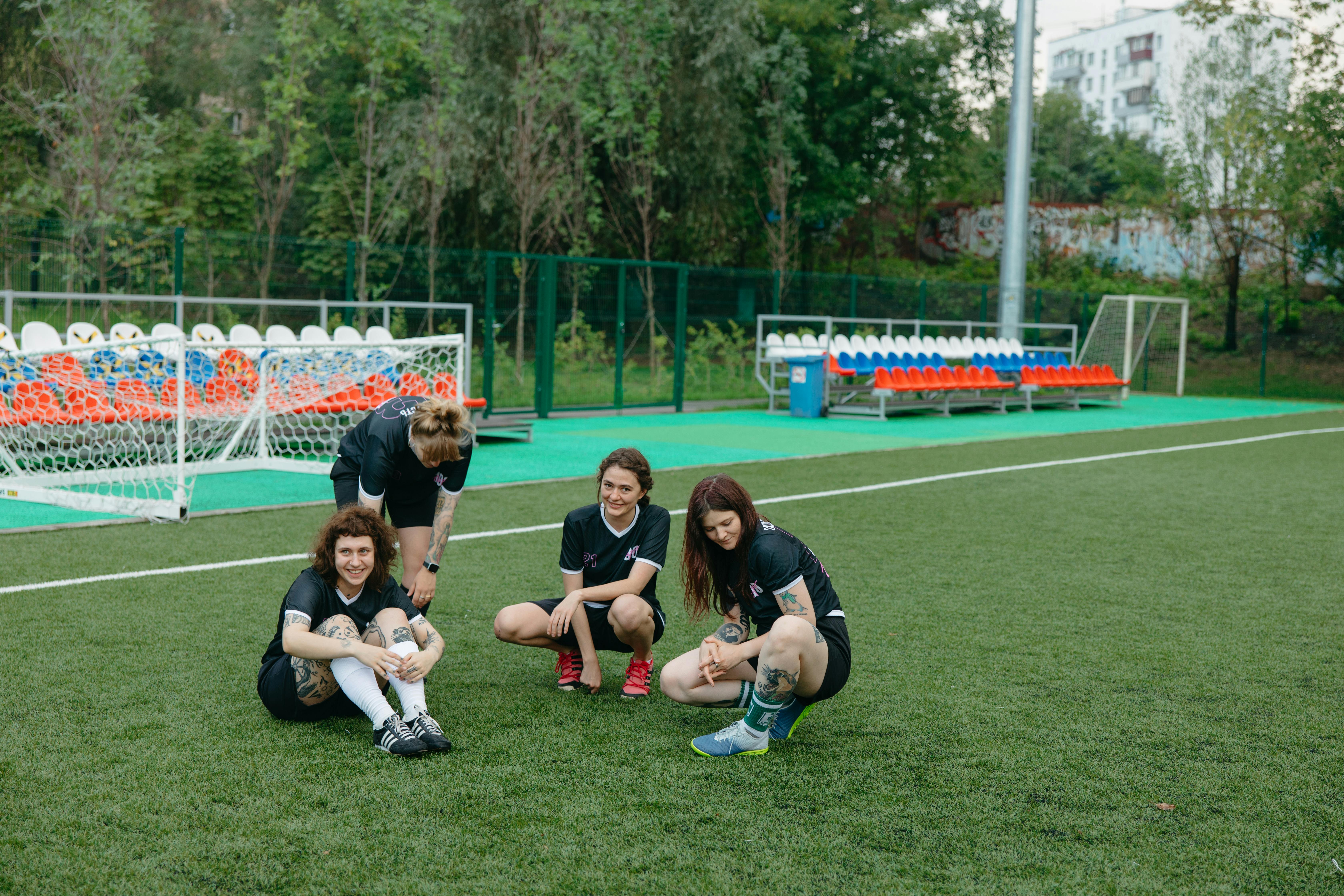 A Group of Girls in Uniform Sitting on Football Field · Free Stock Photo