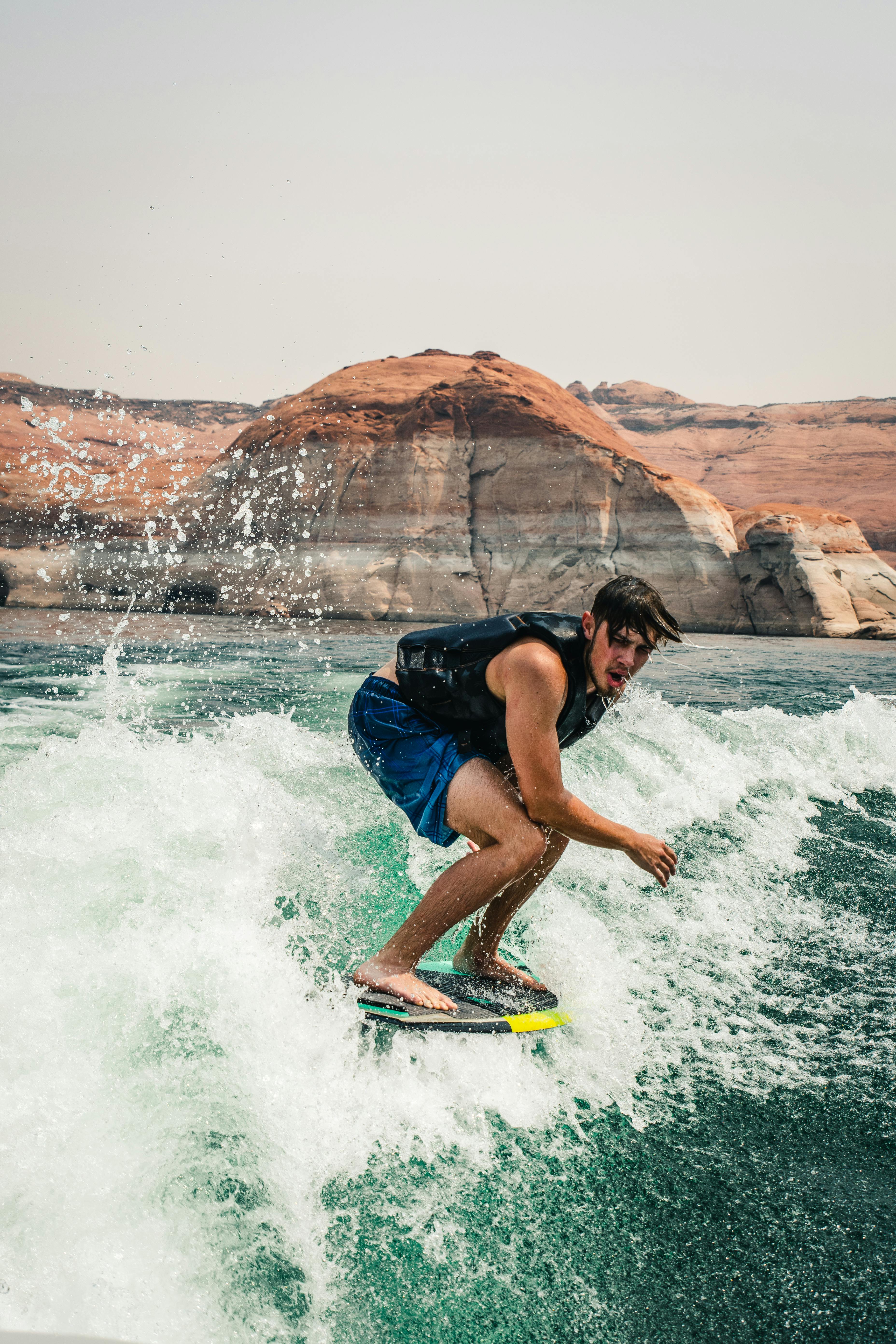 Surfer on Beach Near Rock Formation · Free Stock Photo