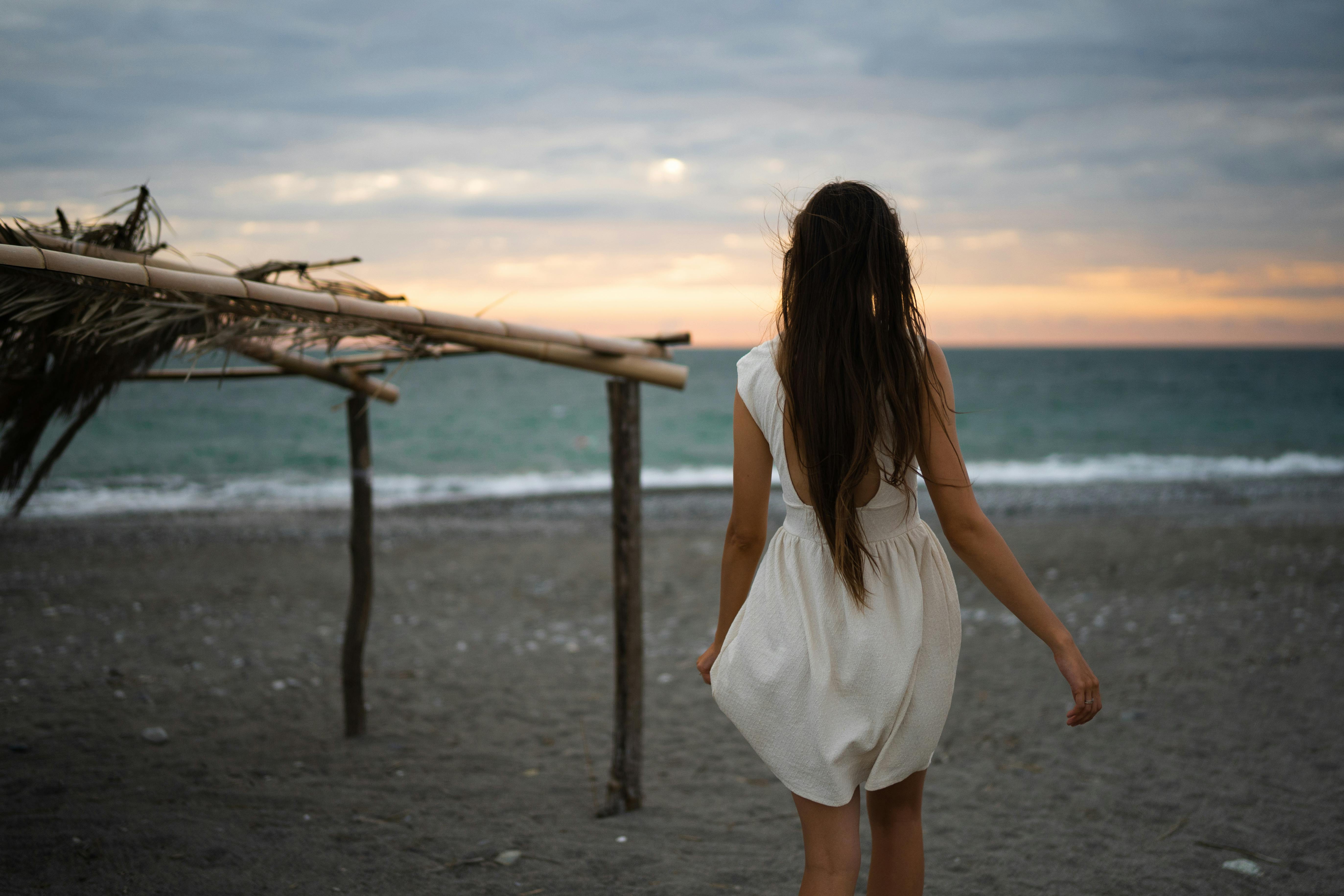 Back View of Person Posing on Windswept Beach · Free Stock Photo