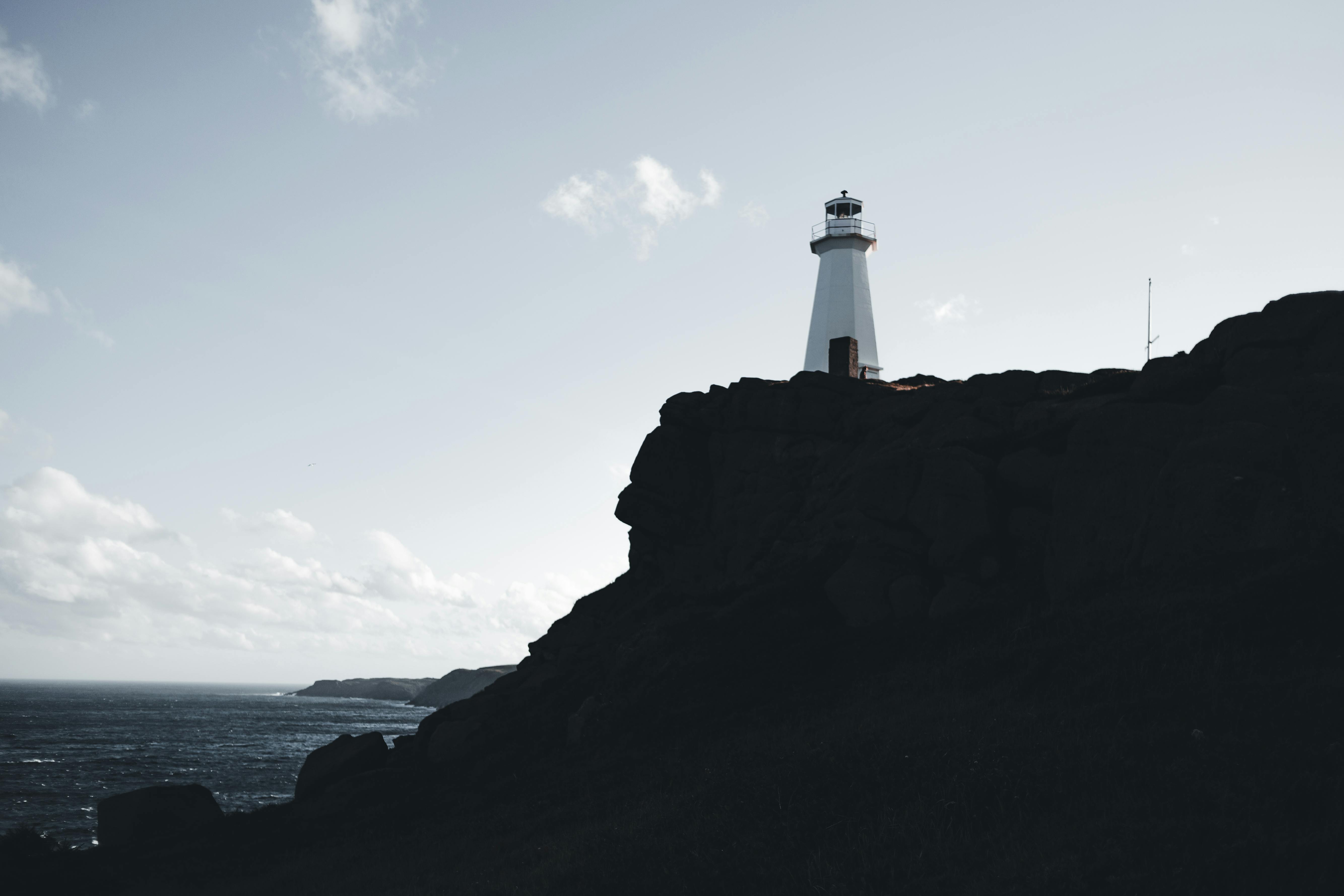 White Lighthouse at the Cliff Near Body of Water · Free Stock Photo