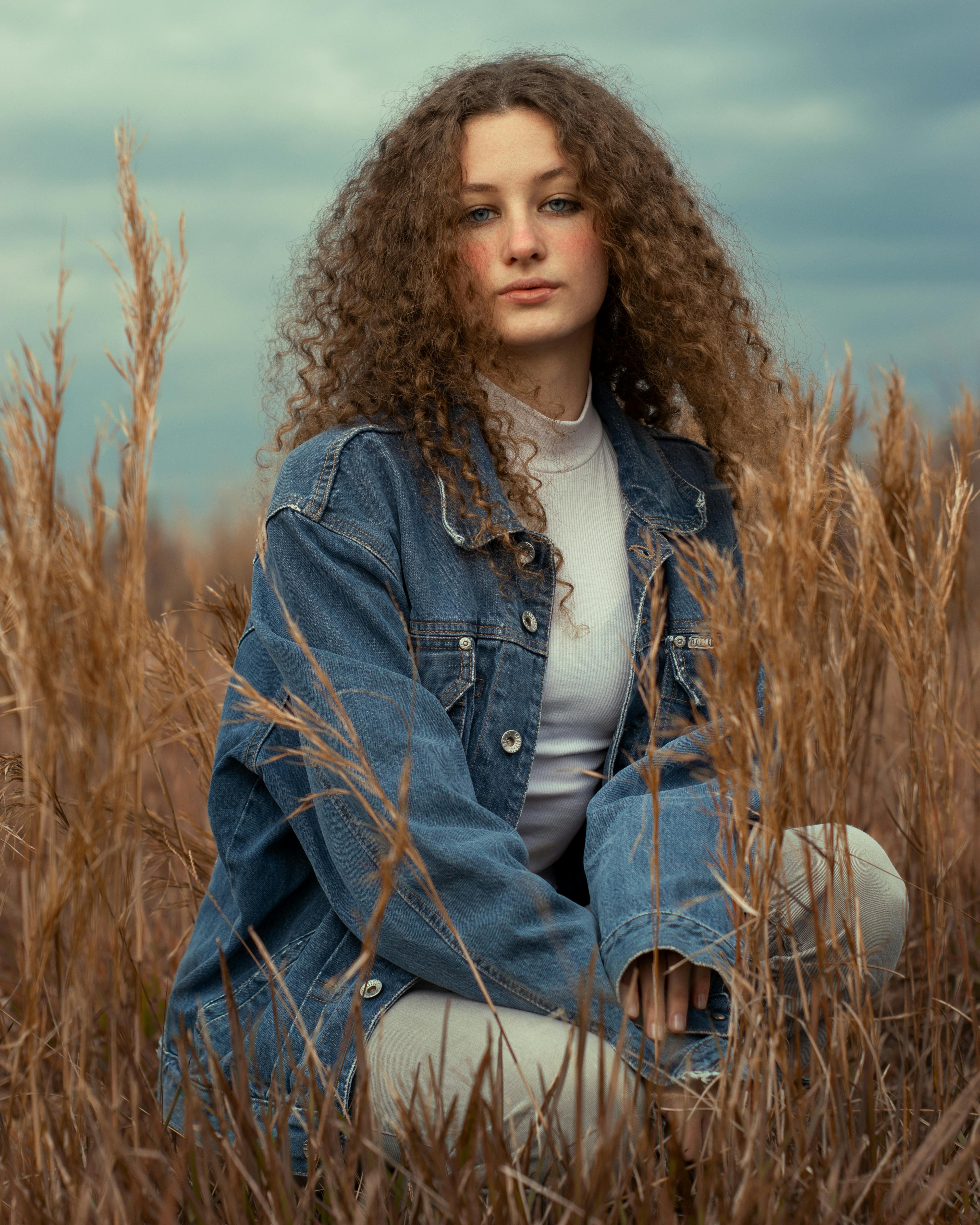 Portrait of Curly Haired Woman in Jeans Crouching · Free Stock Photo