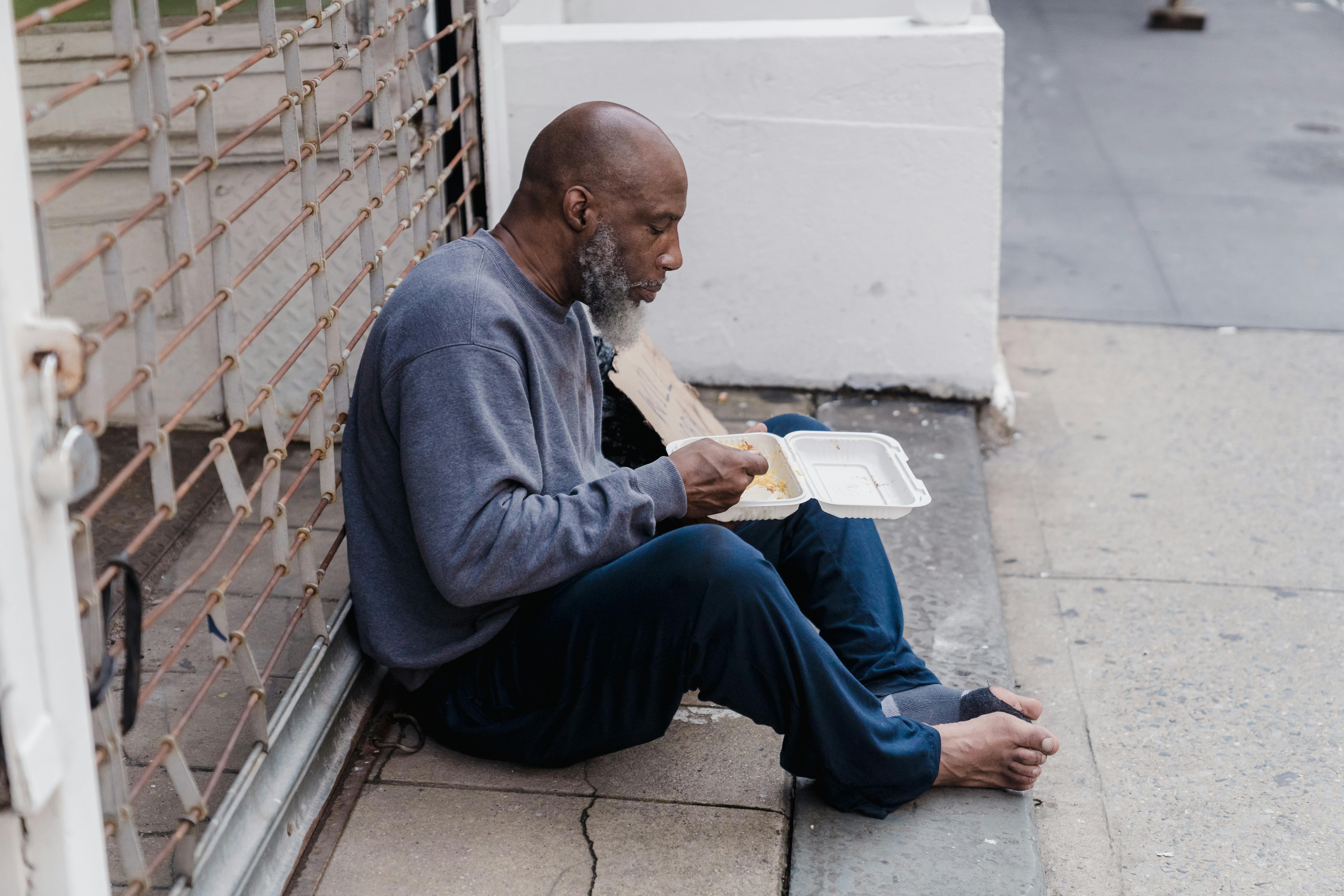 A Man Eating Food on the Sidewalk · Free Stock Photo