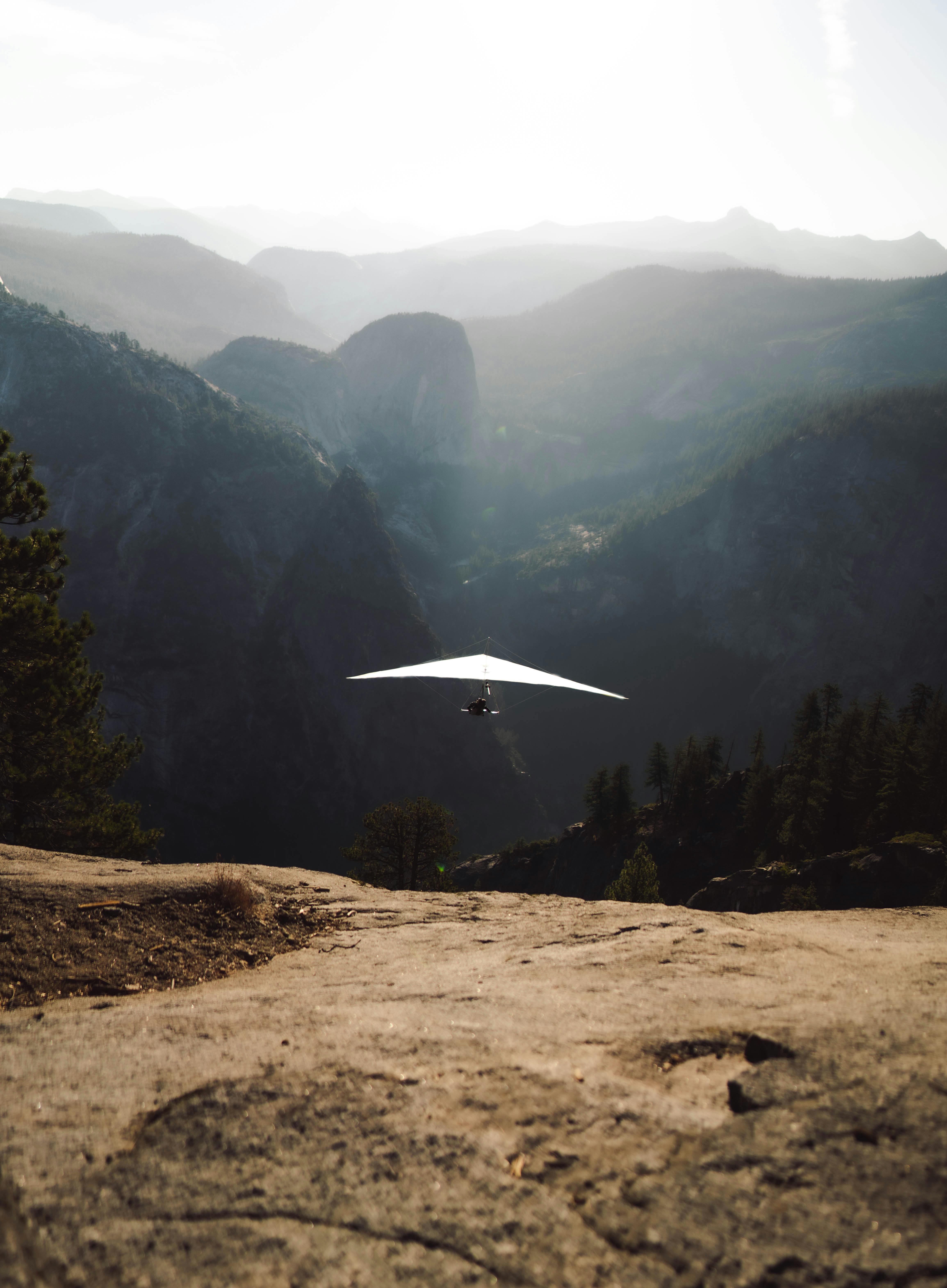 Person in Parachute Gliding Above Mountains · Free Stock Photo