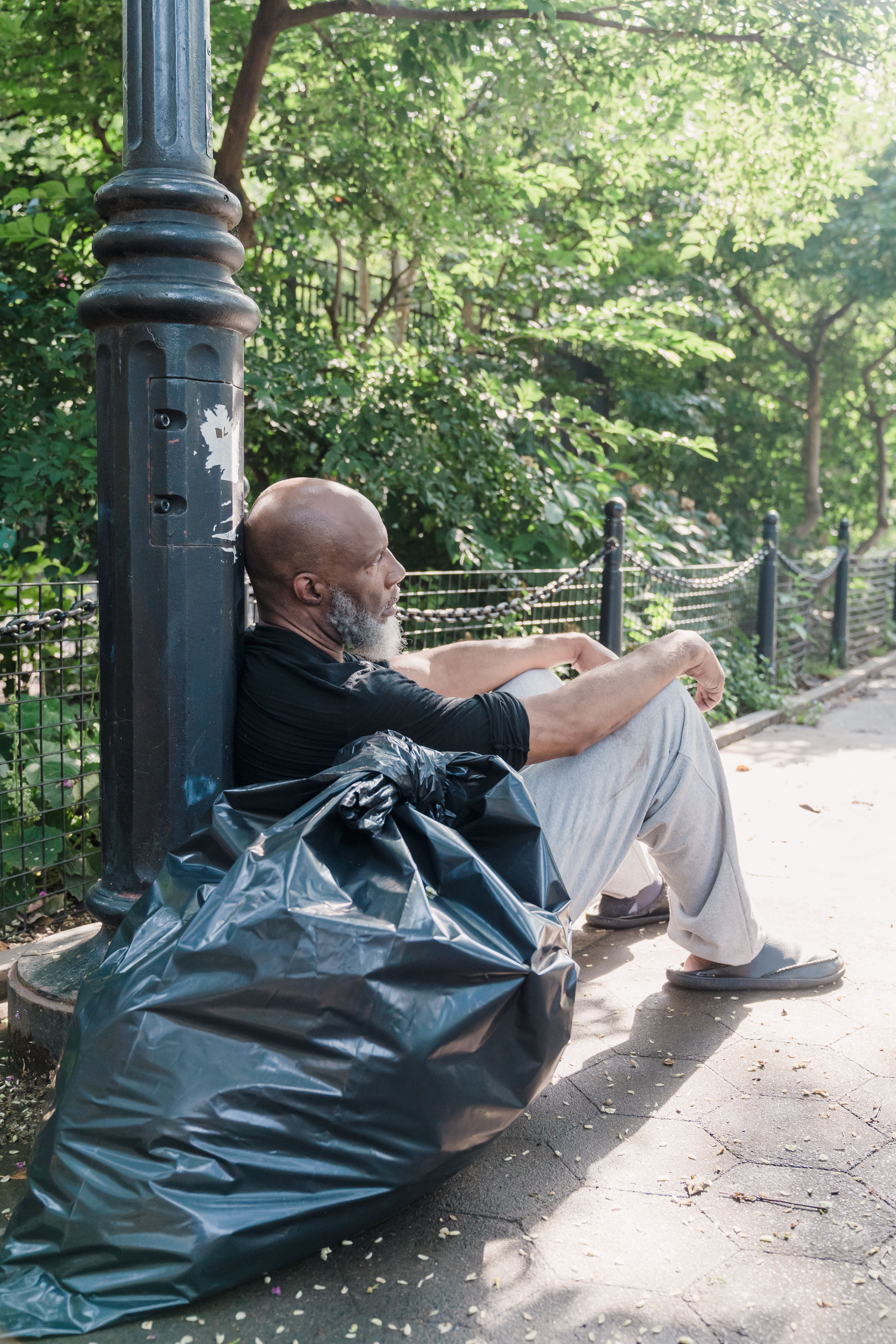 A Bearded Man Sitting on the Ground Leaning on a Post · Free Stock Photo