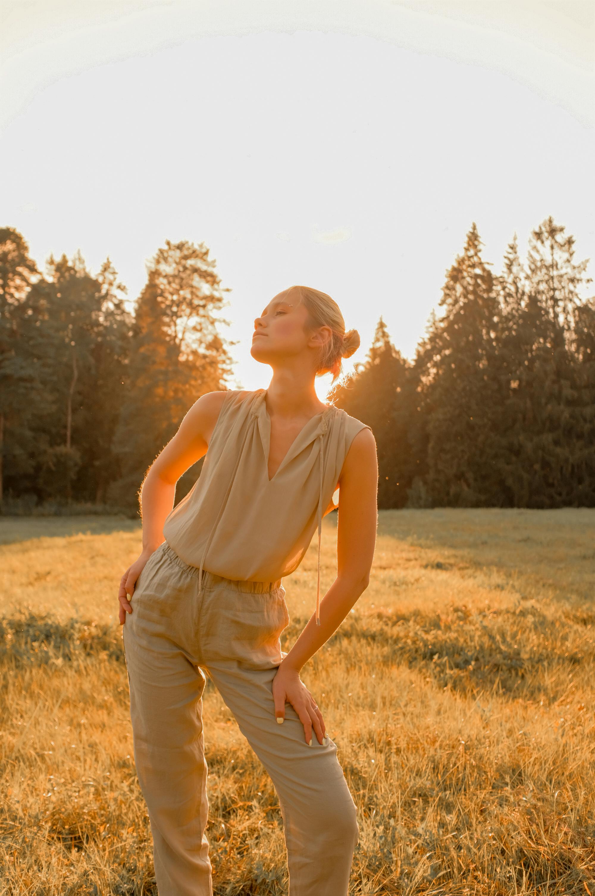 Young girl standing back on meadow at sunset · Free Stock Photo