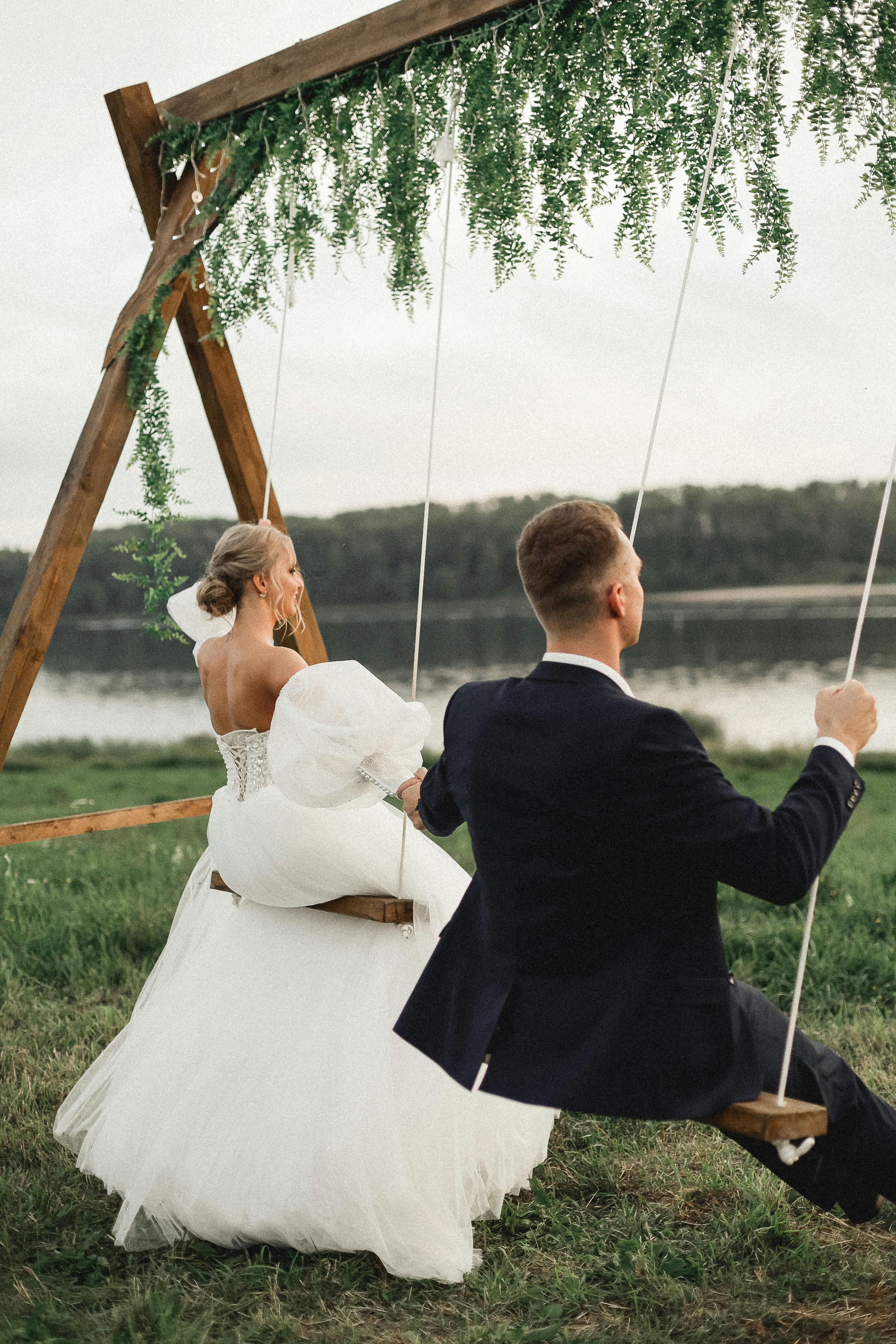 Couple Holding Hands While Sitting on Swing · Free Stock Photo