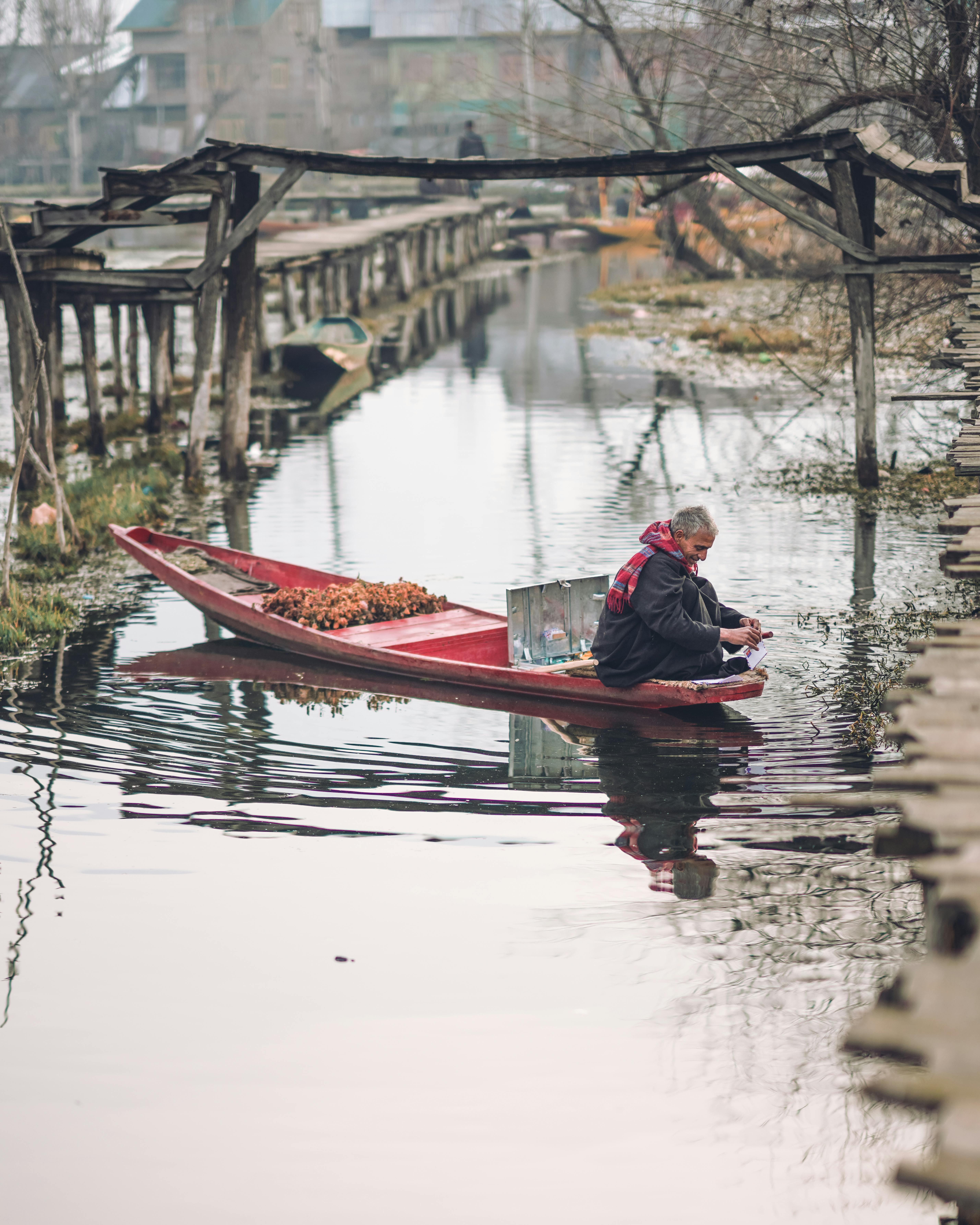 Man in Black Jacket Riding on a Red Boat on River · Free Stock Photo