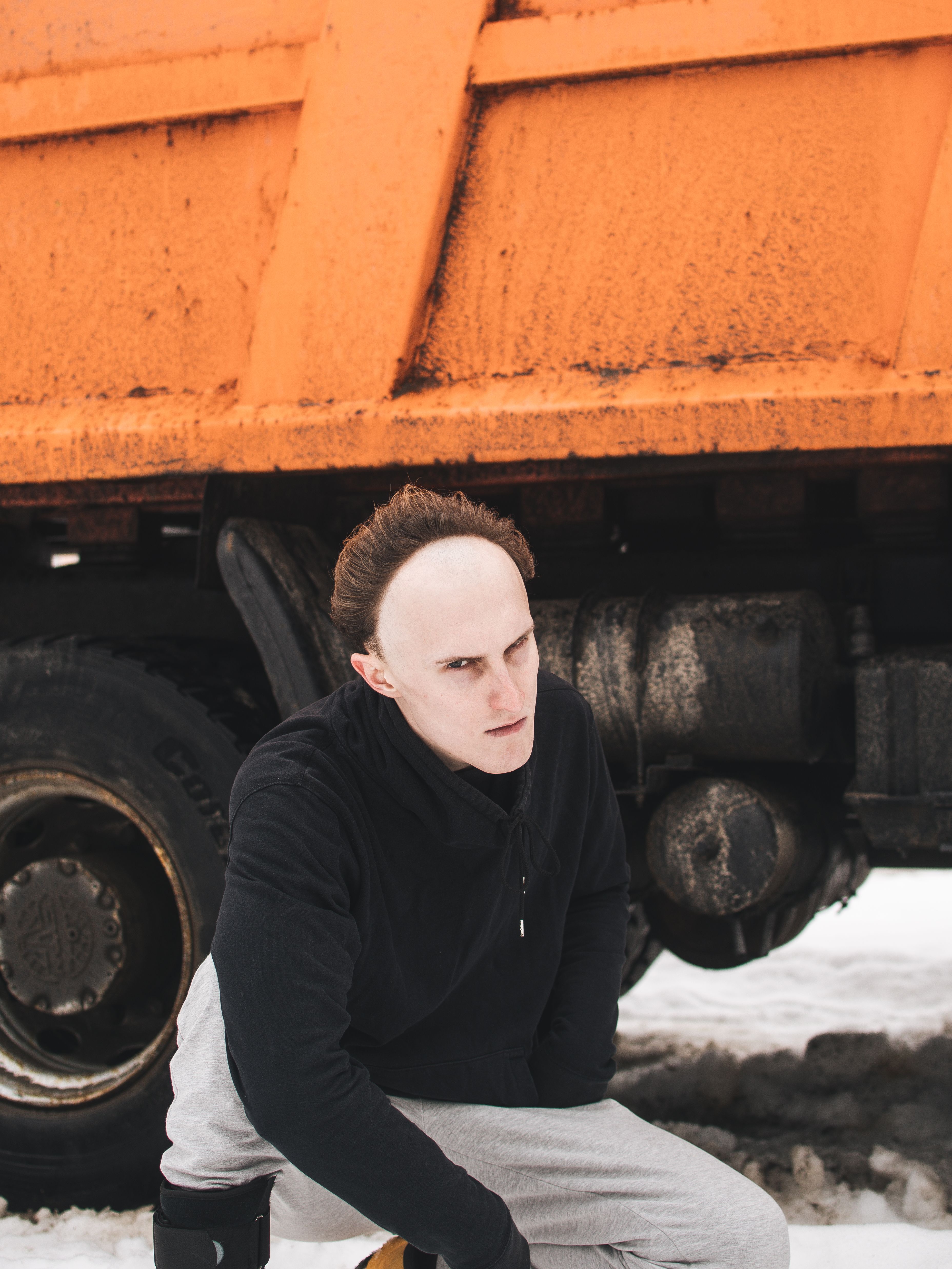 A Weird Looking Man Sitting Beside a Yellow Truck · Free Stock Photo