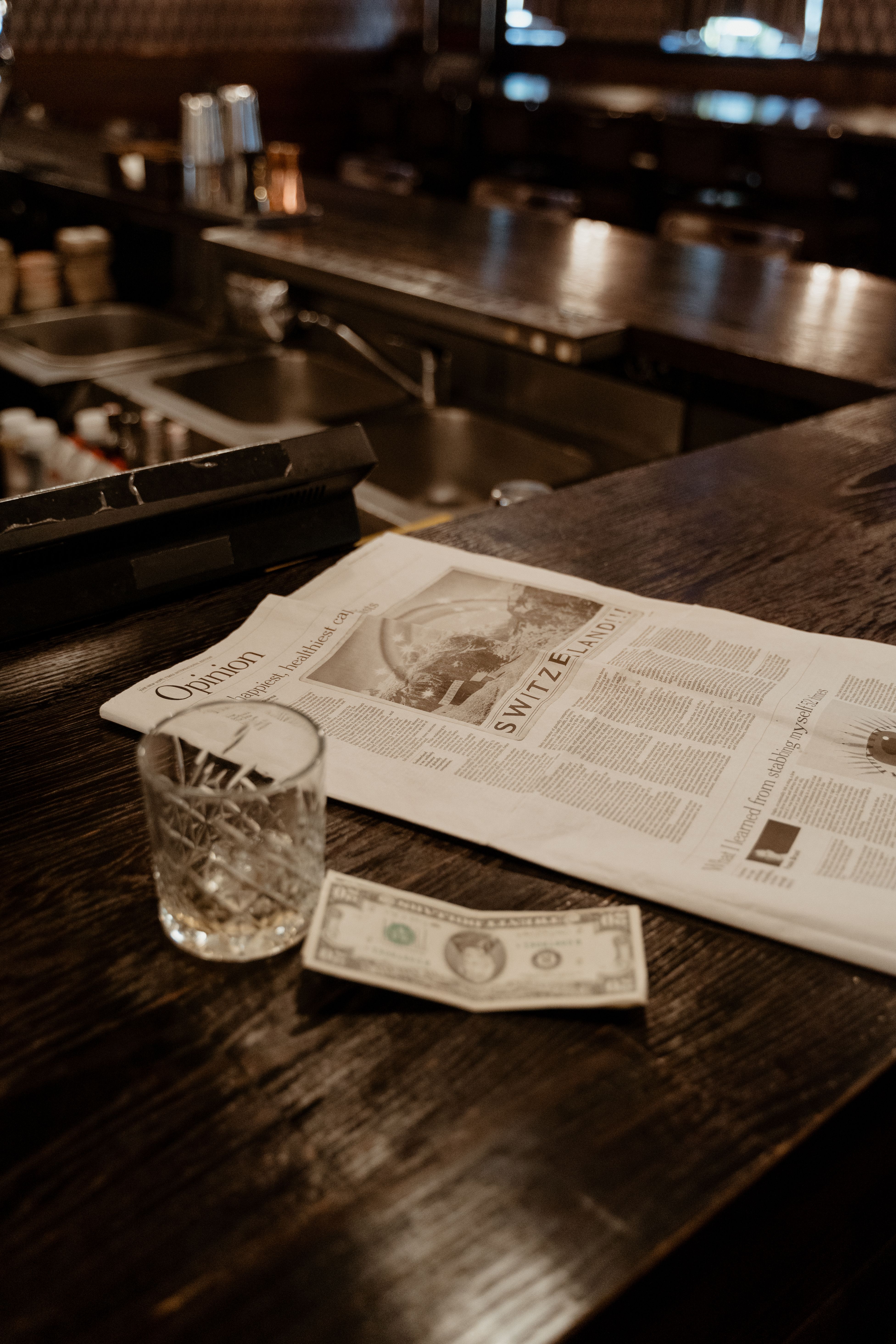 A Dollar Bill Beside a Clear Drinking Glass on Brown Wooden Table ...