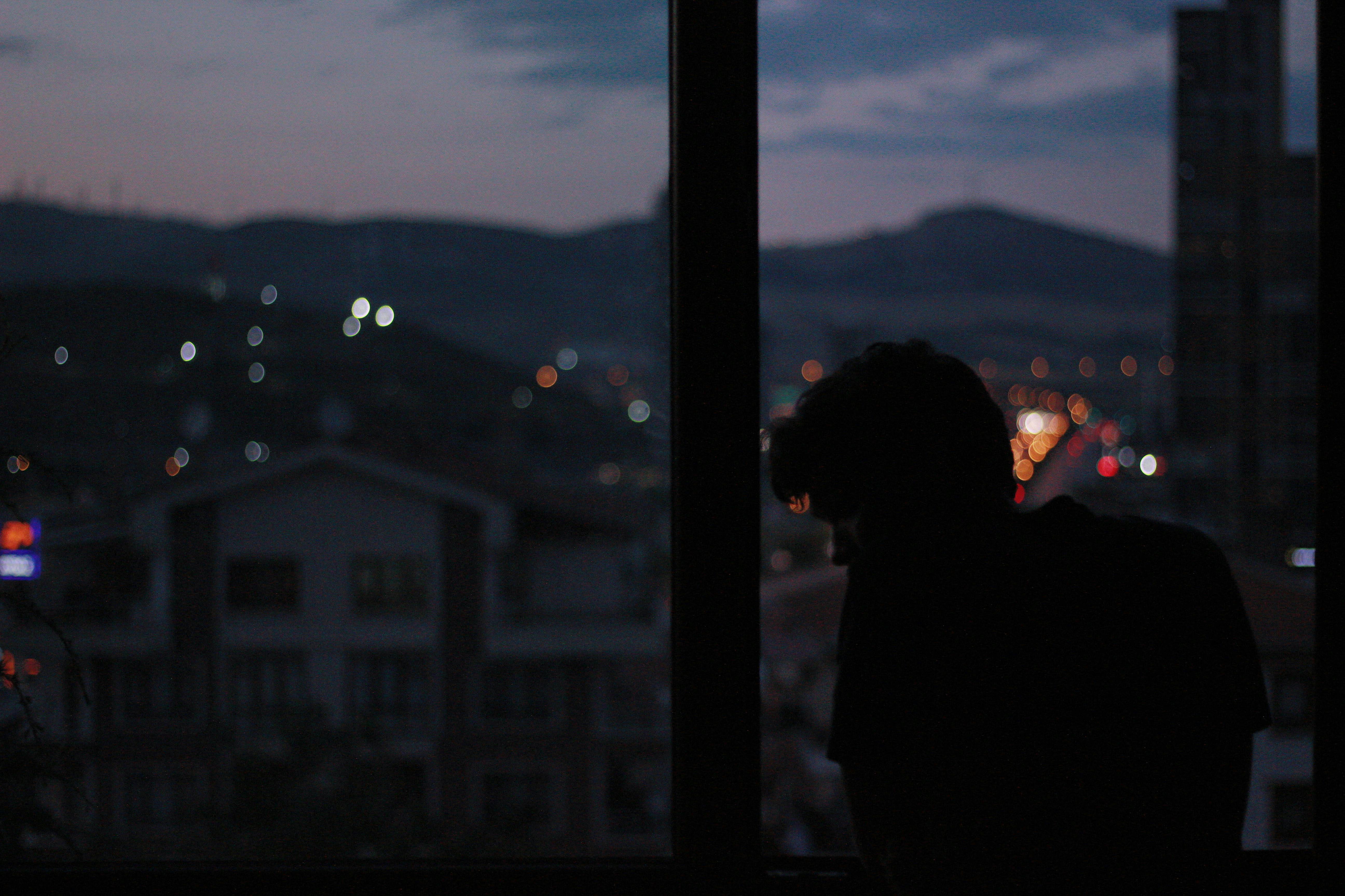 Silhouette of a Man Looking at the Window at Night · Free Stock Photo