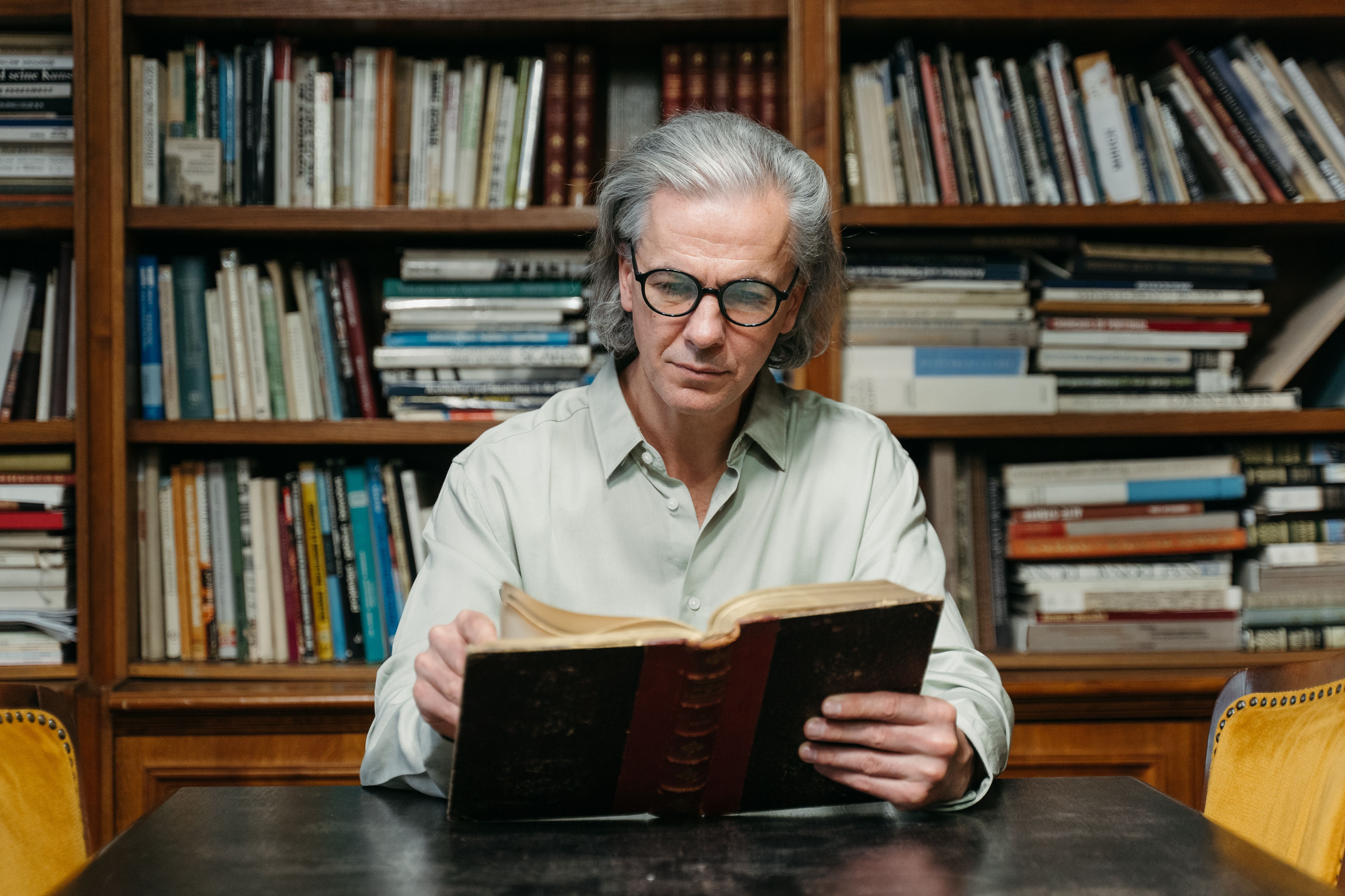 An Elderly Man Reading a Book at a Library · Free Stock Photo