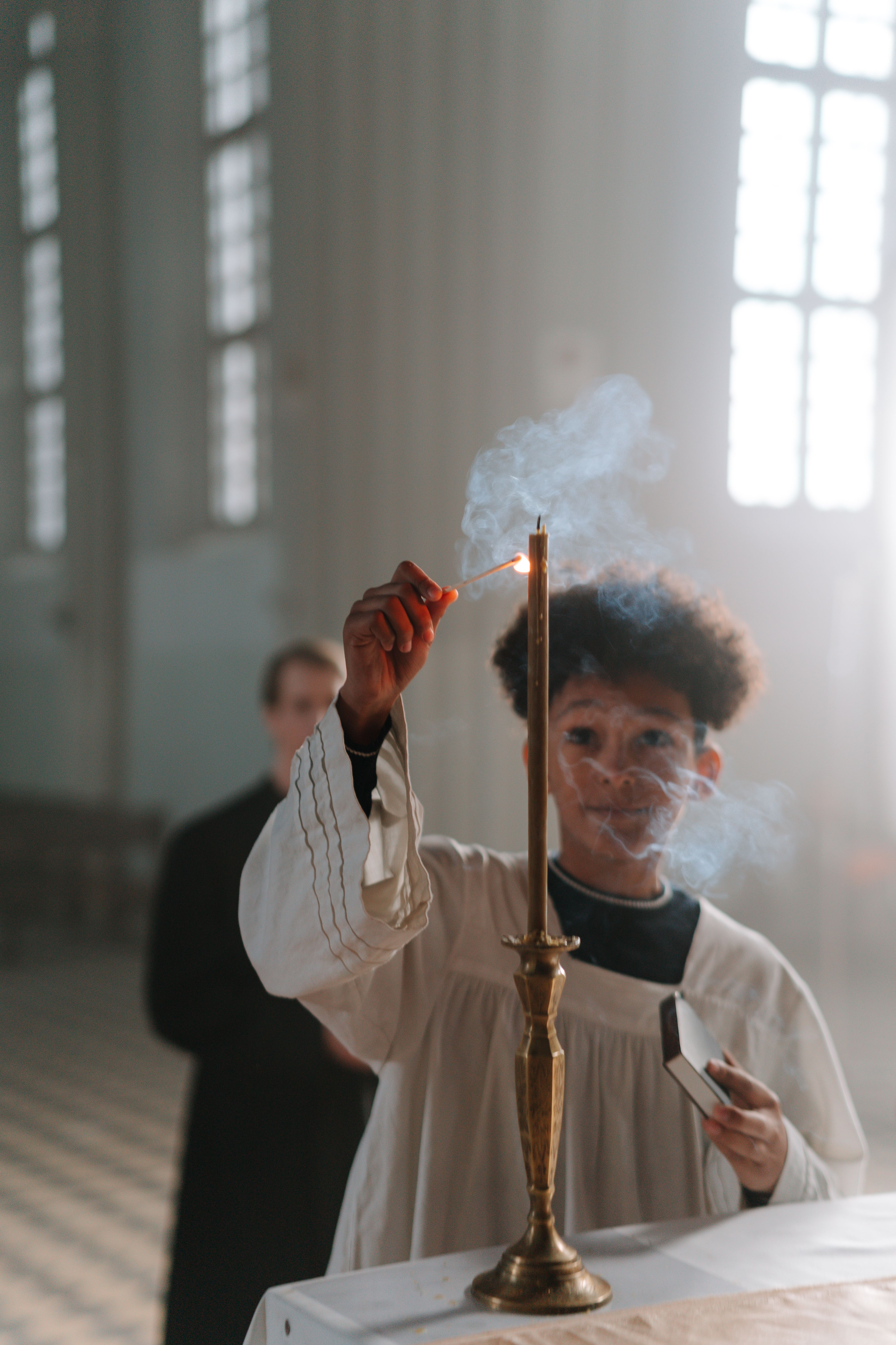 Boy Lighting a Candle in a Church and Priest Standing behind Him · Free ...