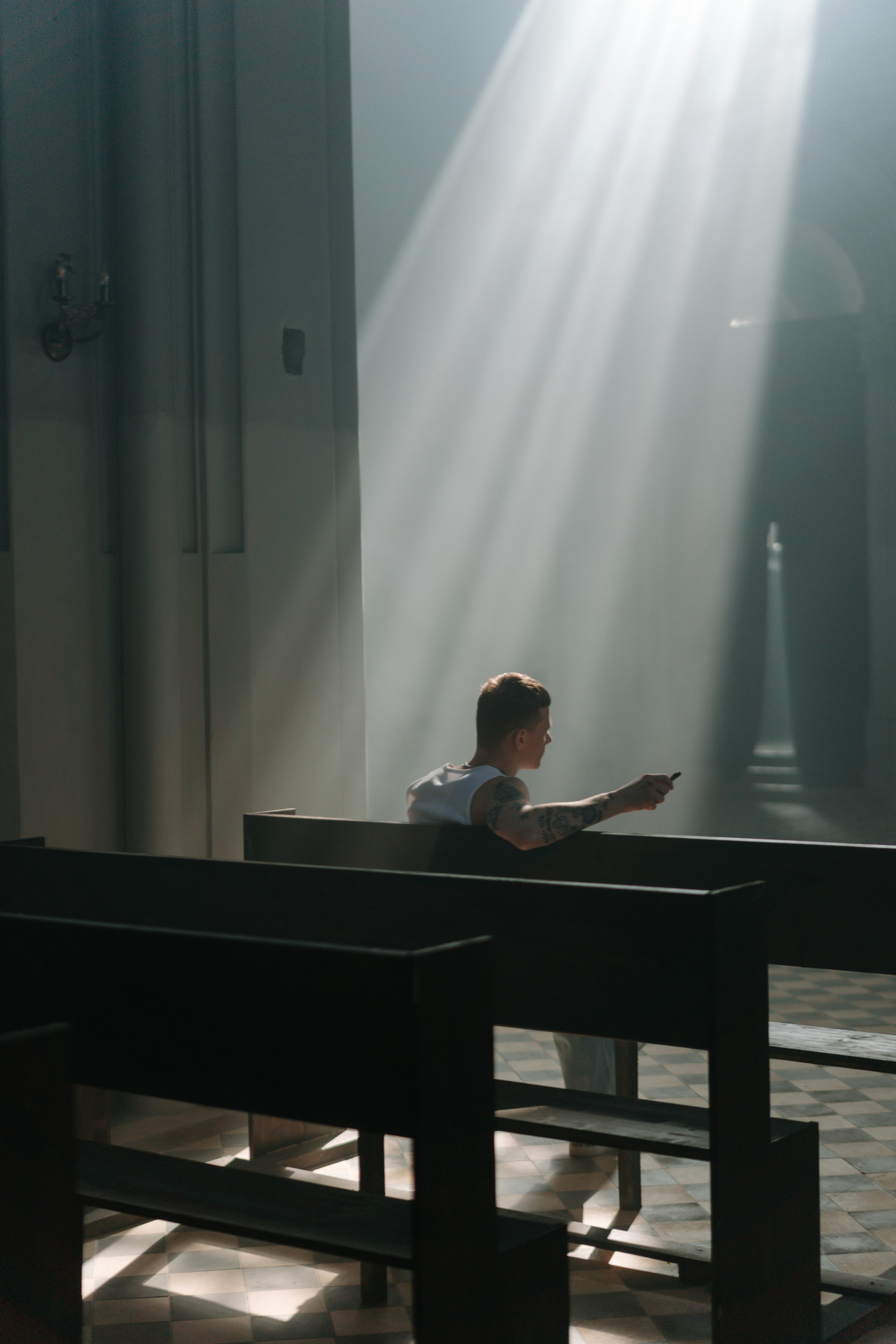 Man Sitting on a Pew Holding a Cross · Free Stock Photo